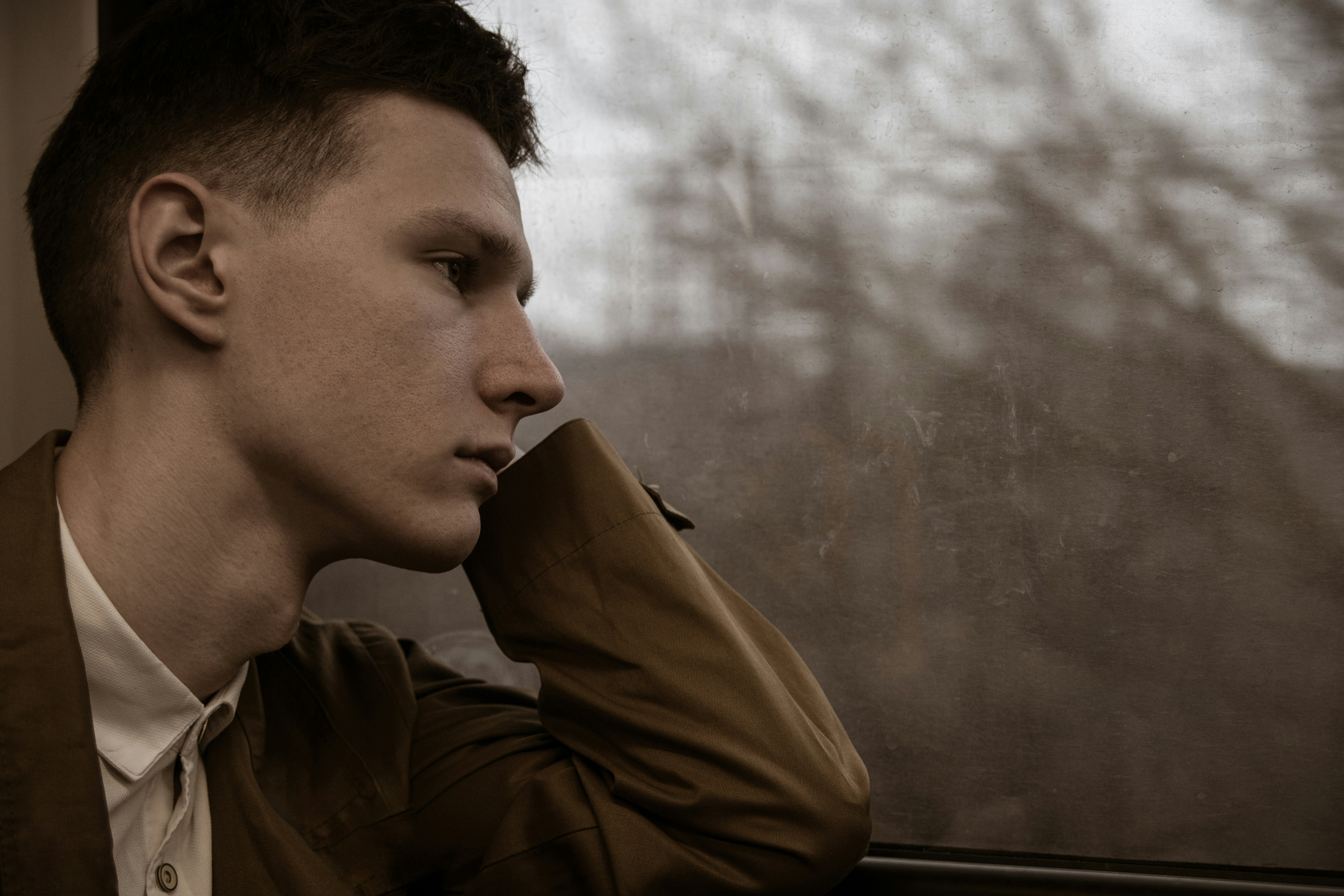 The man stares thoughtfully out the train window.