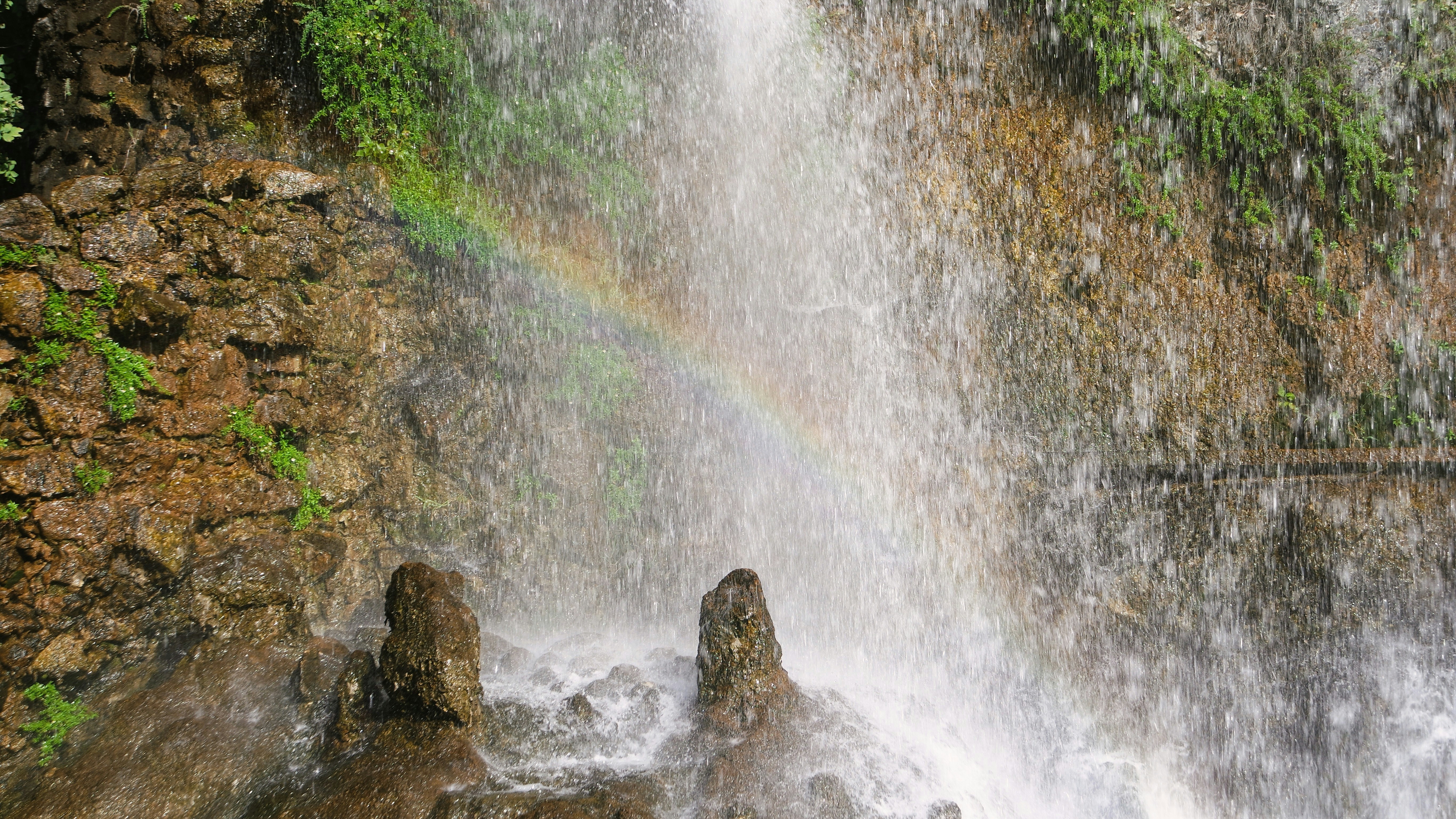 Rainbow over Mist and Twin Basalt Spires in a Forest Waterfall
