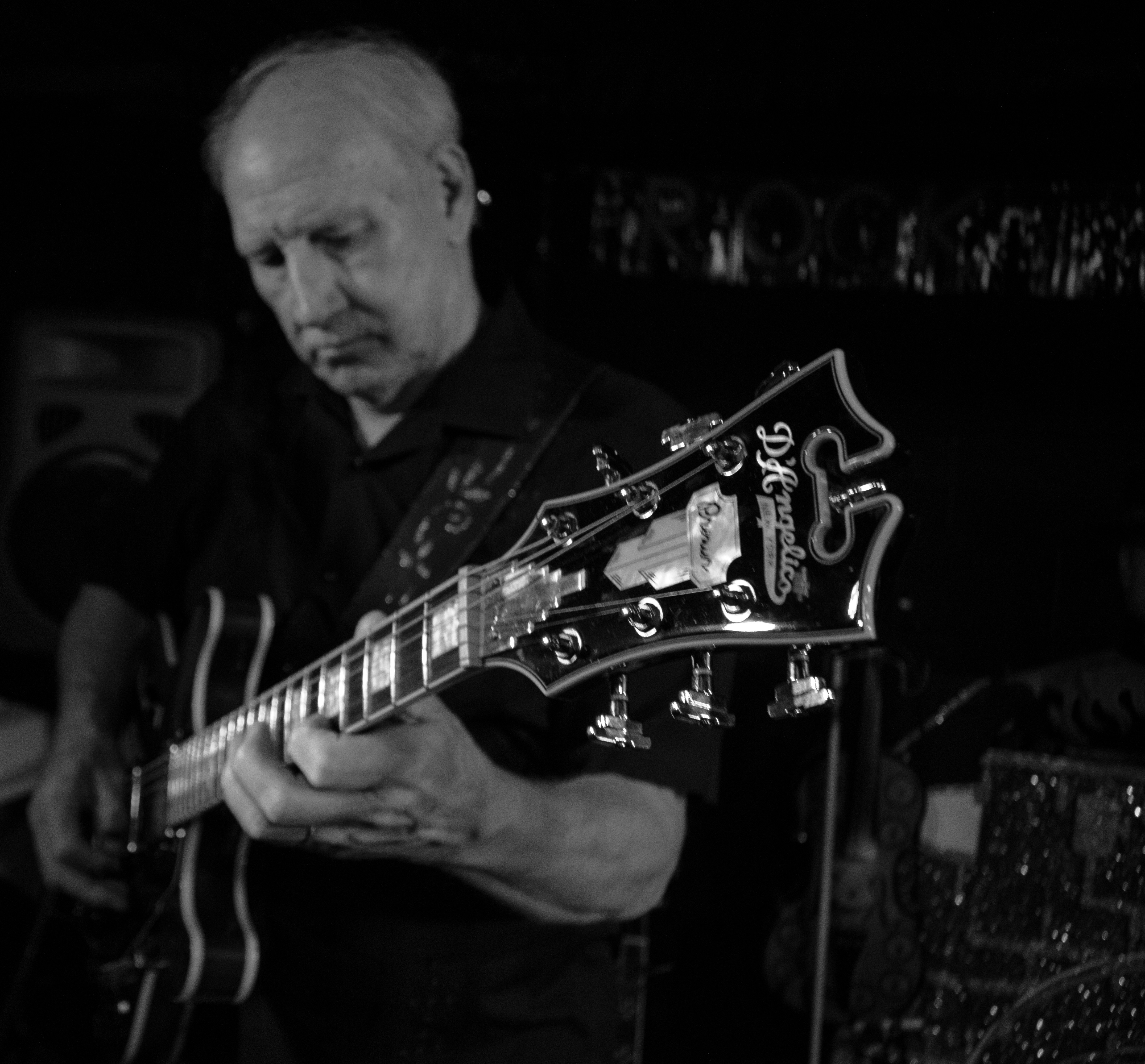 Gibson in Shadow: Focused fretwork on a dim club stage