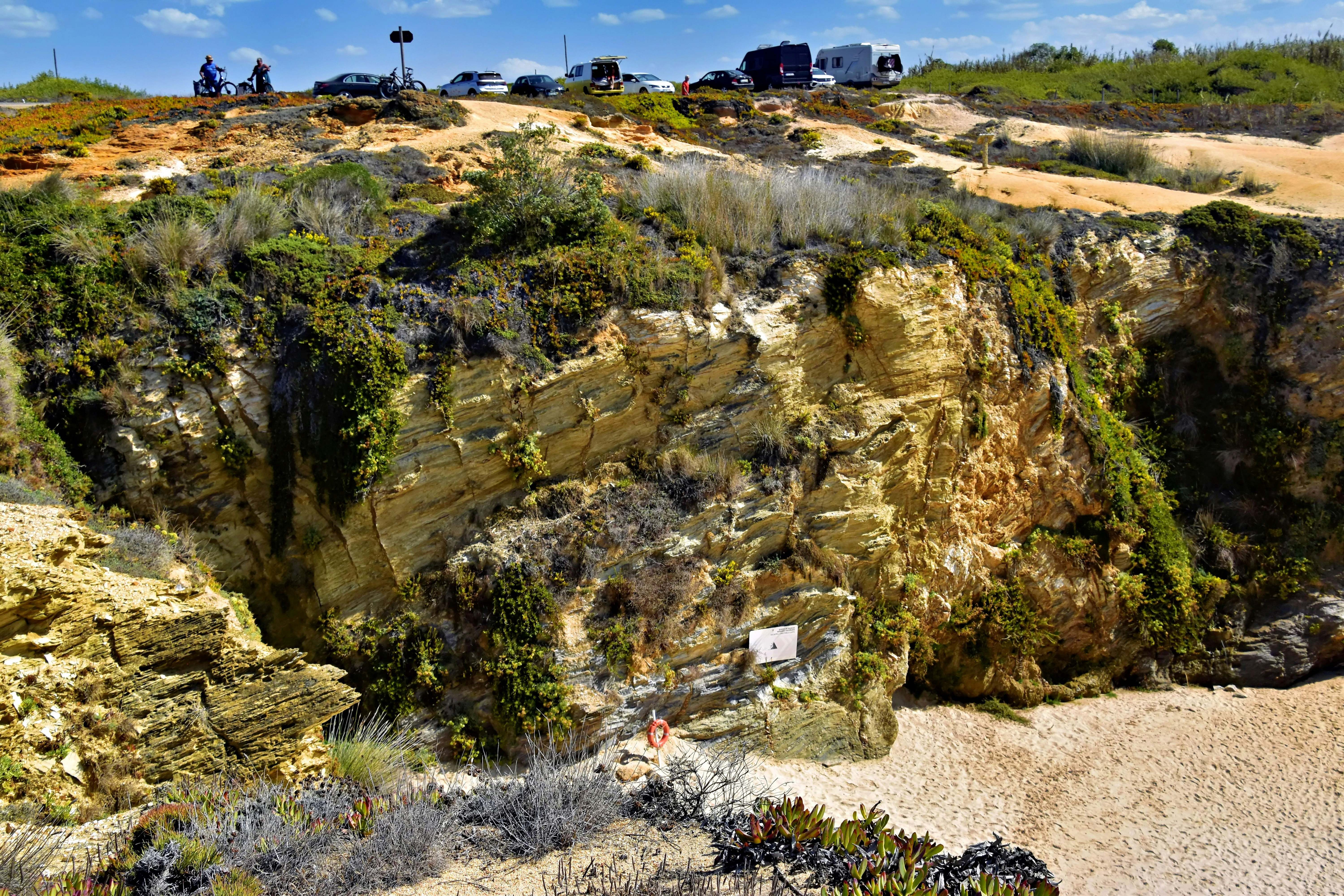 Overlooked Cliffs: Sunlit Stratified Rocks Framing a Pebble Beach Below