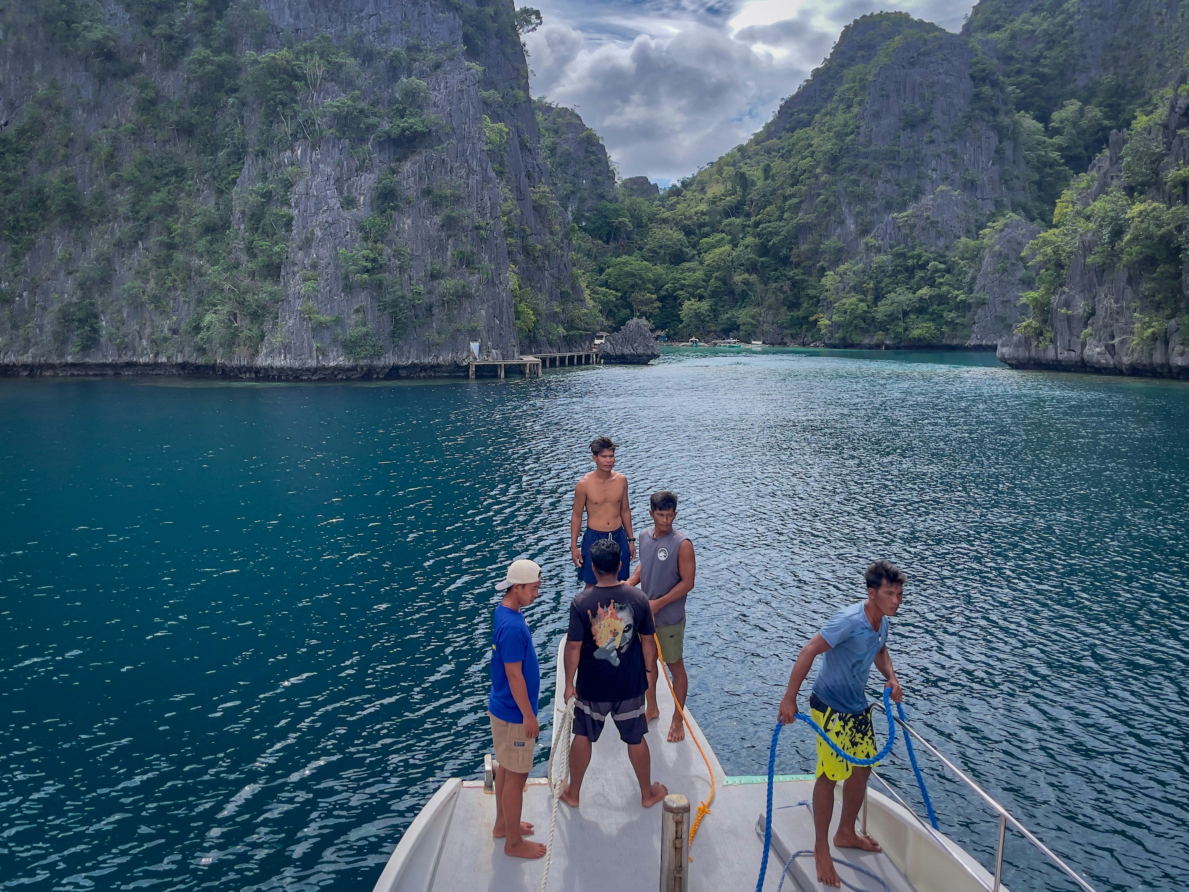 Five Explorers on a Compact Boat Amid Teal Waters and Towering Karst