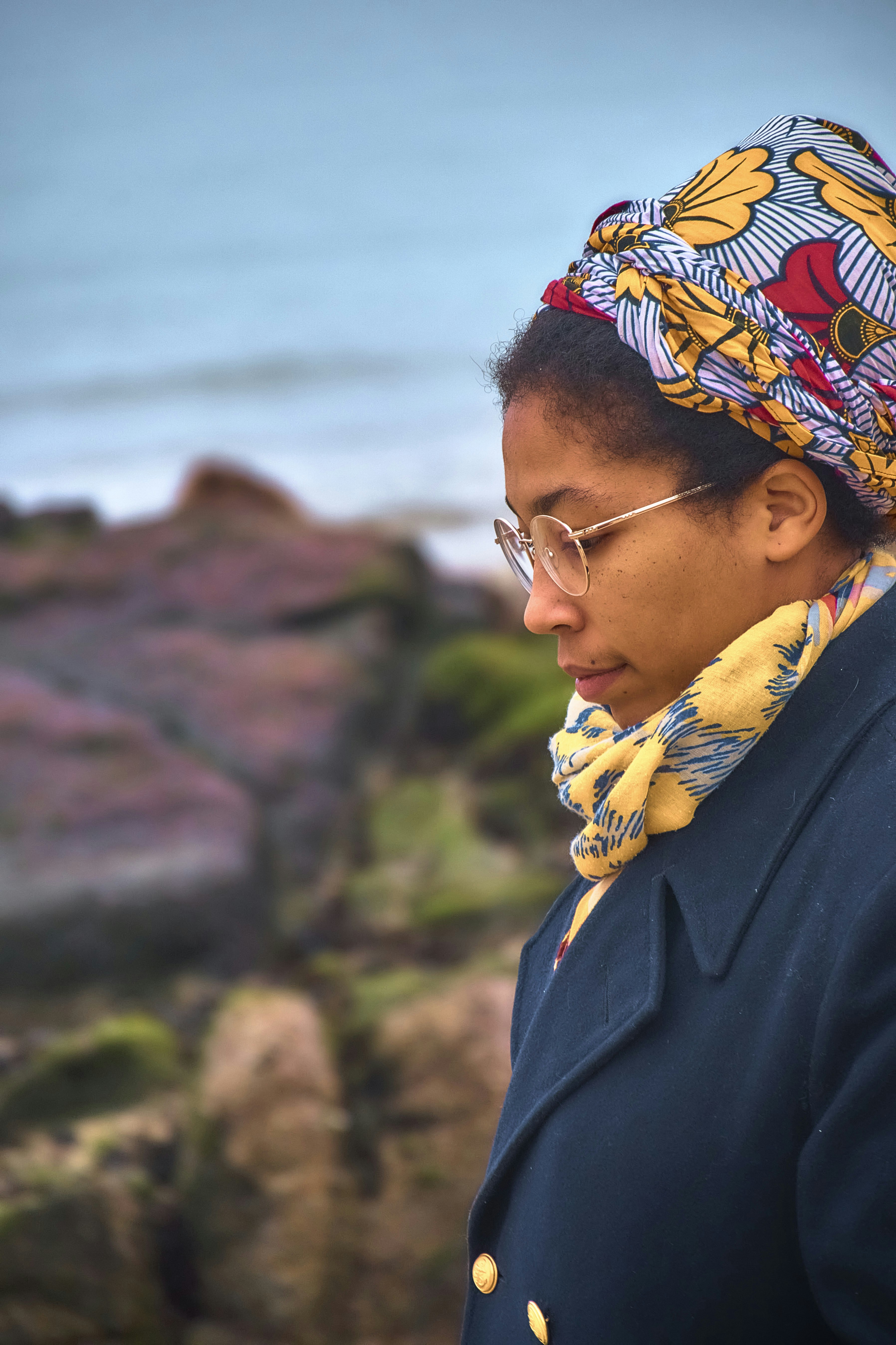 Rugged Coast Portrait: A Colorful Headwrap Meets Quiet Gaze