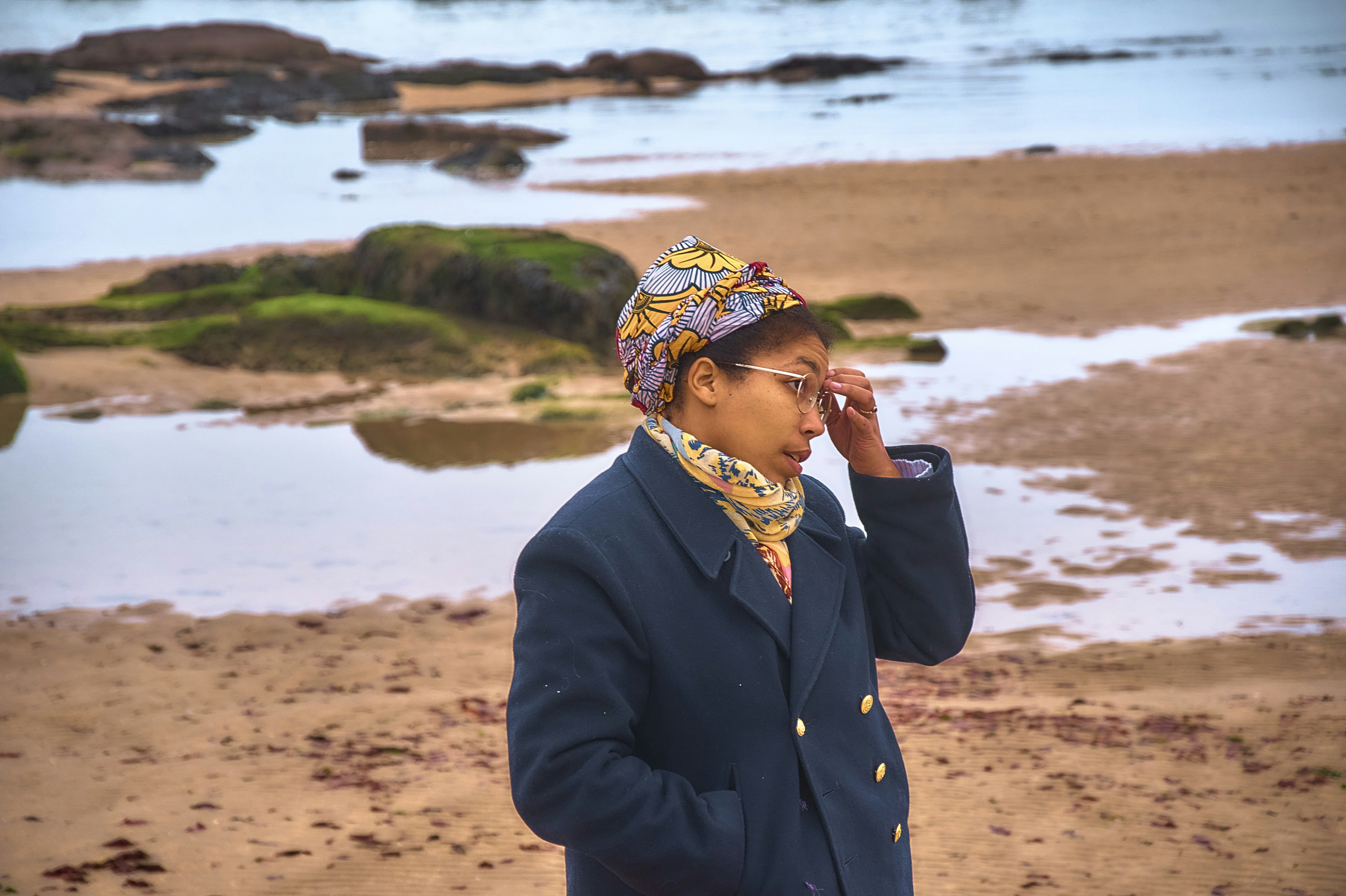 Coastal Quiet: Portrait in a Warm Coat and Colorful Turban by Tidal Sands