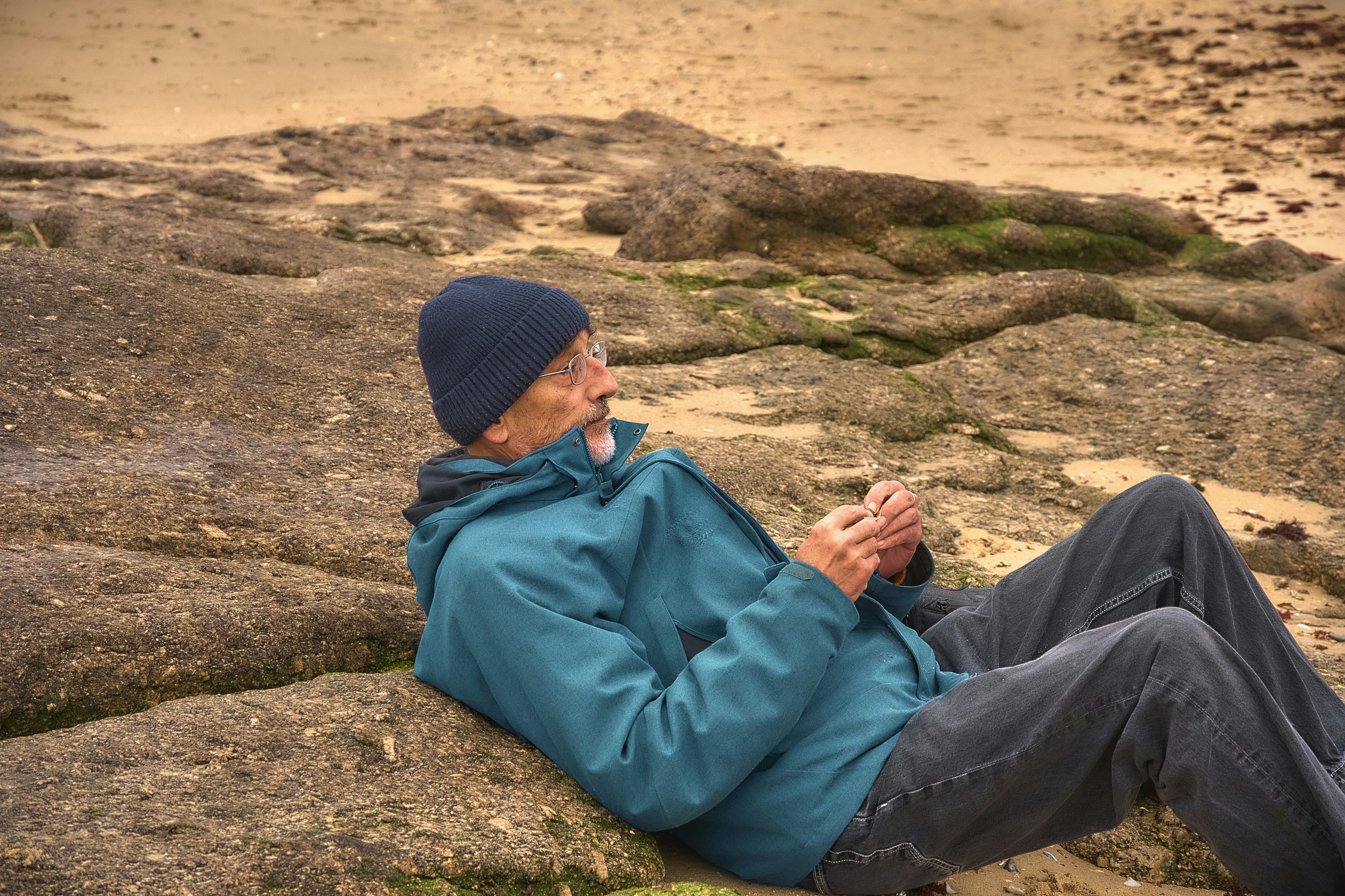 Seaside Recline: A Weathered Wanderer Pauses by Mossy Rocks