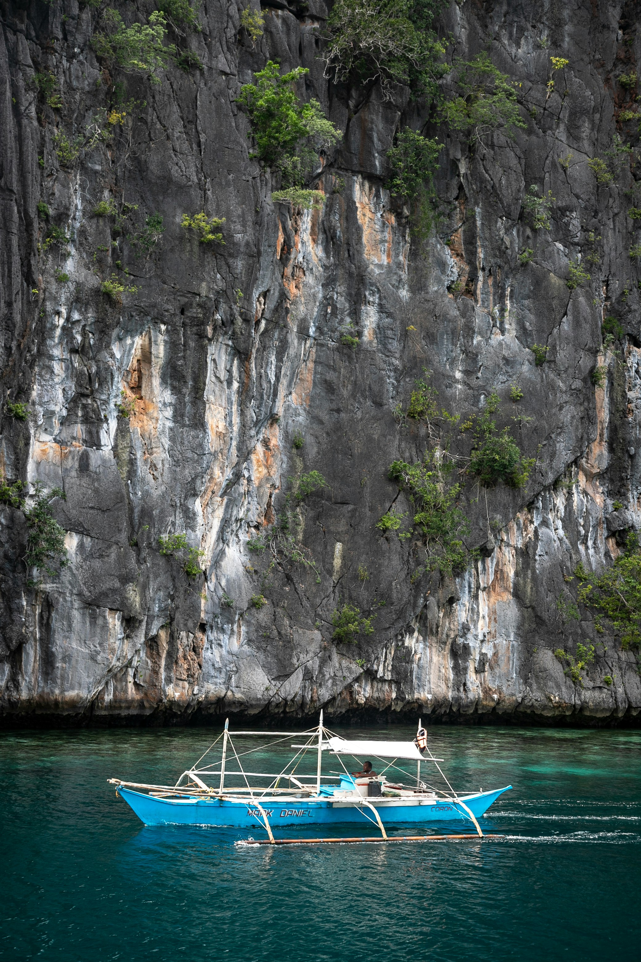 Azure Boat at the Foot of a Variegated Cliff Over Turquoise Waters