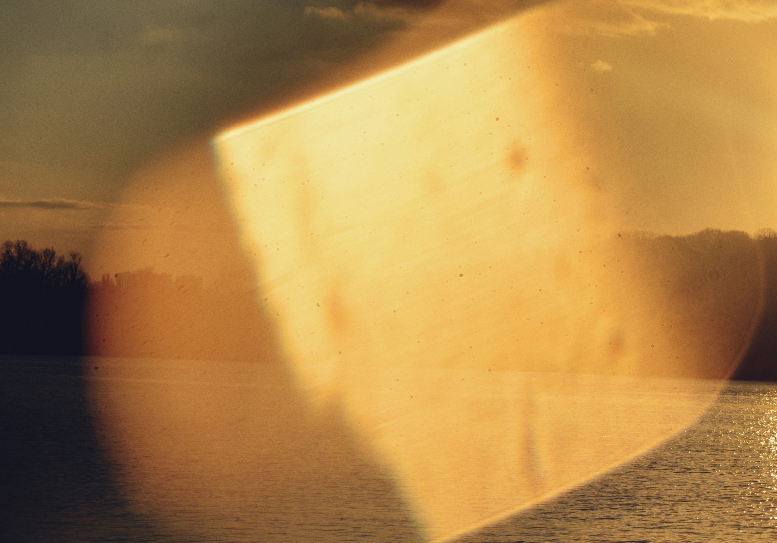 Golden Echo on the Horizon: A Sunset Framed by Lens Flare