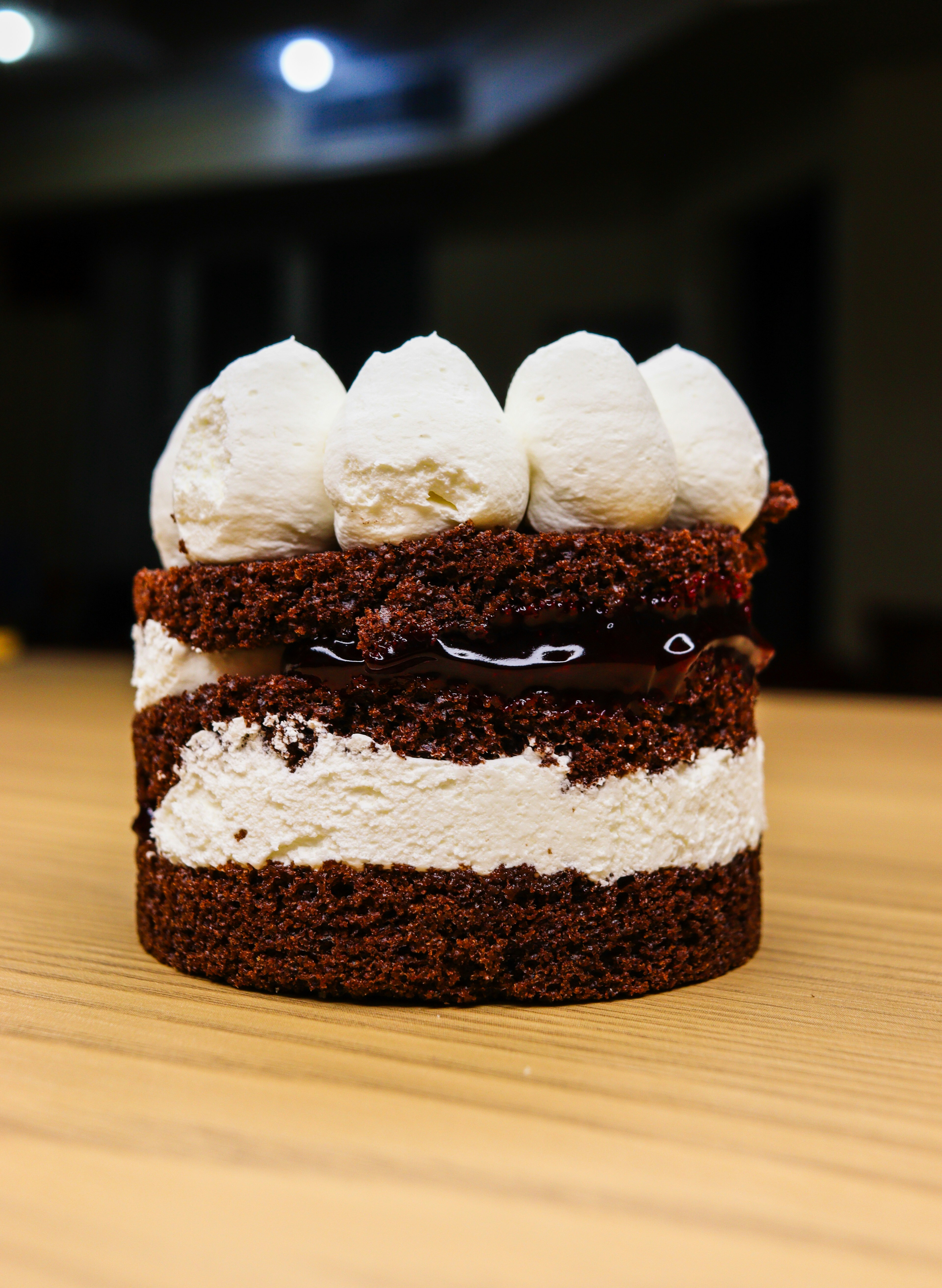 Three Cream Peaks Crown a Chocolate Layer Cake Under Soft Studio Light