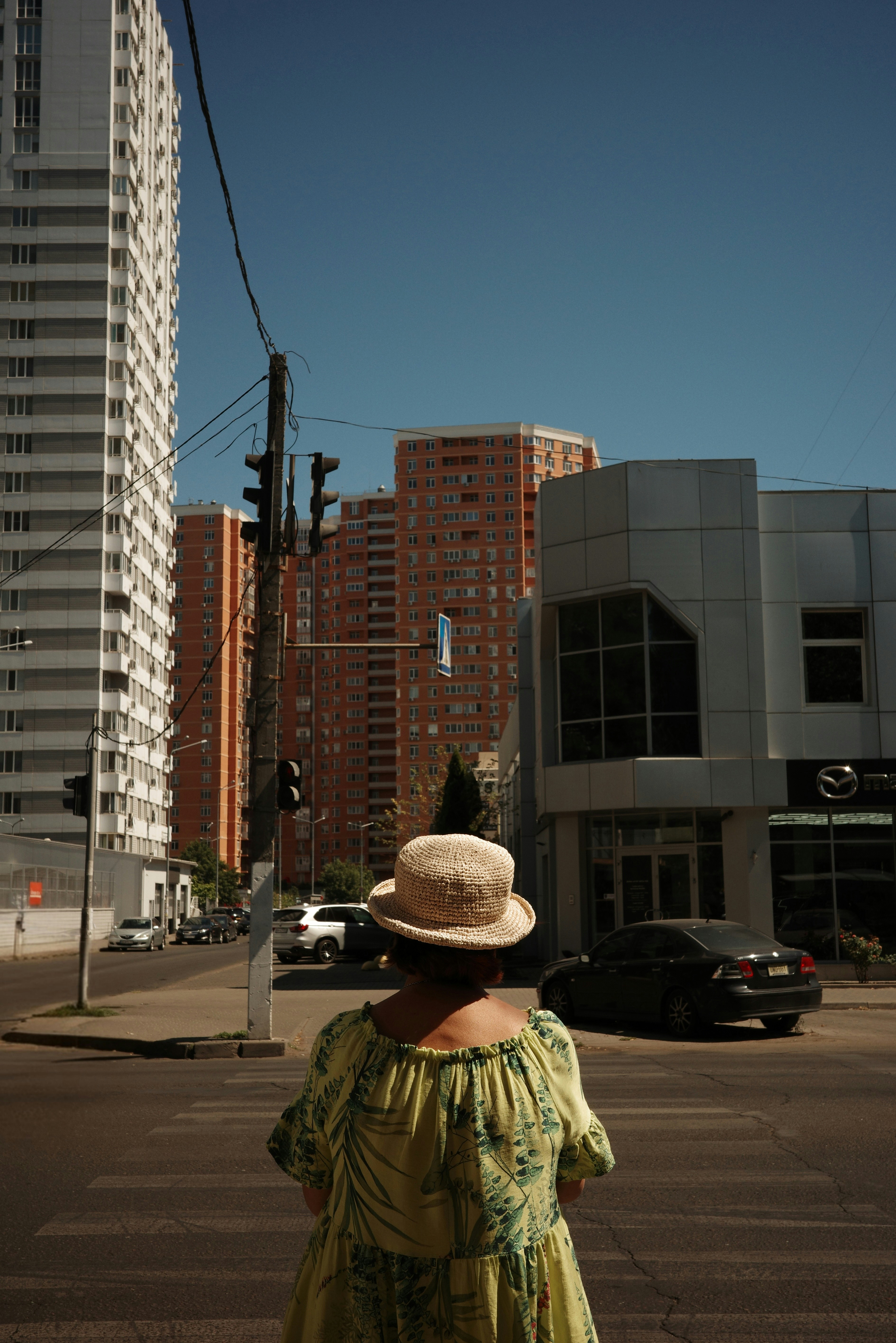 Crosswalk Reverie: A Woman in Green at the Edge of the City