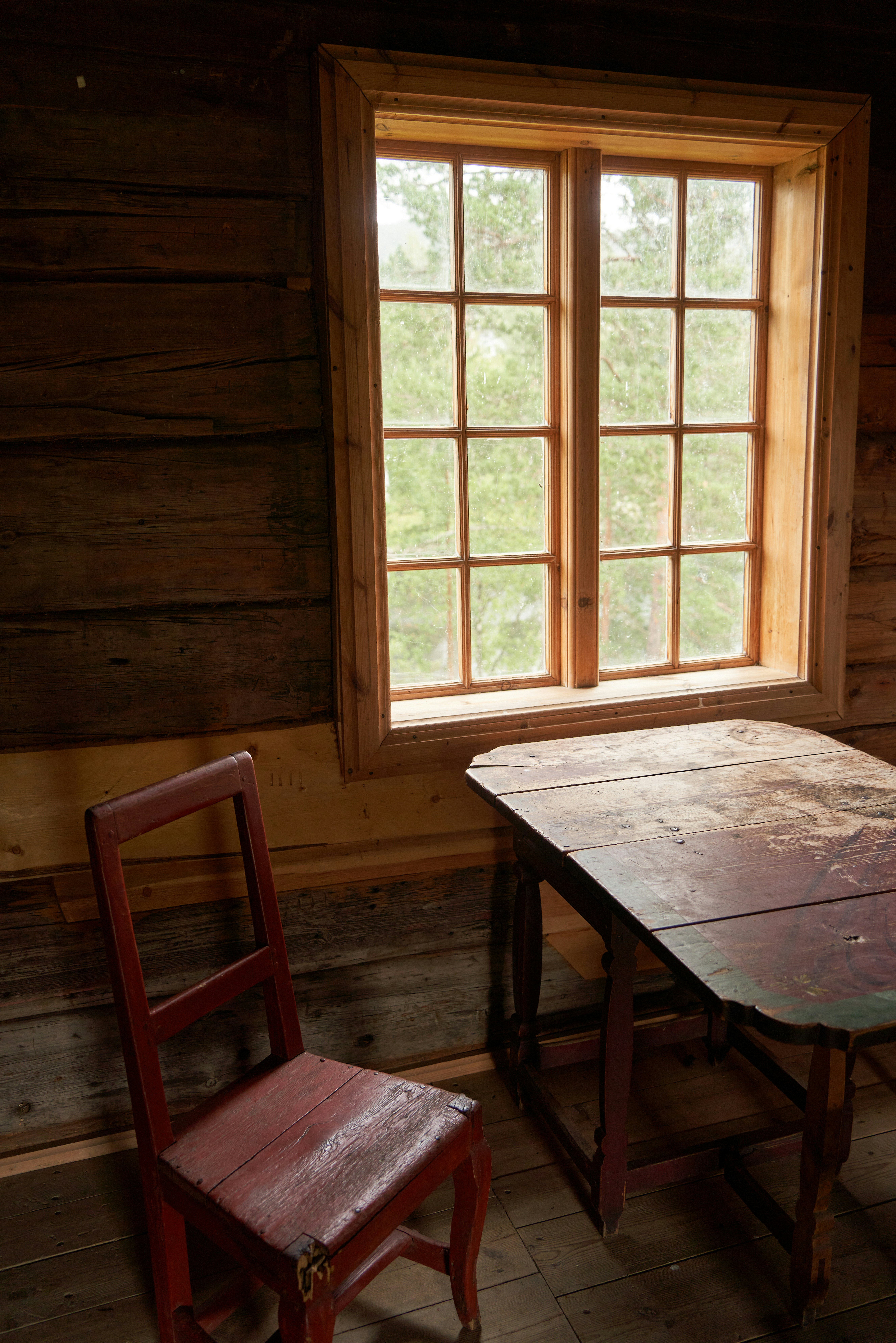 Old traditional log house interior with a chair, table by a window in the Sigdal skanzen, near to Prestfoss, Norway