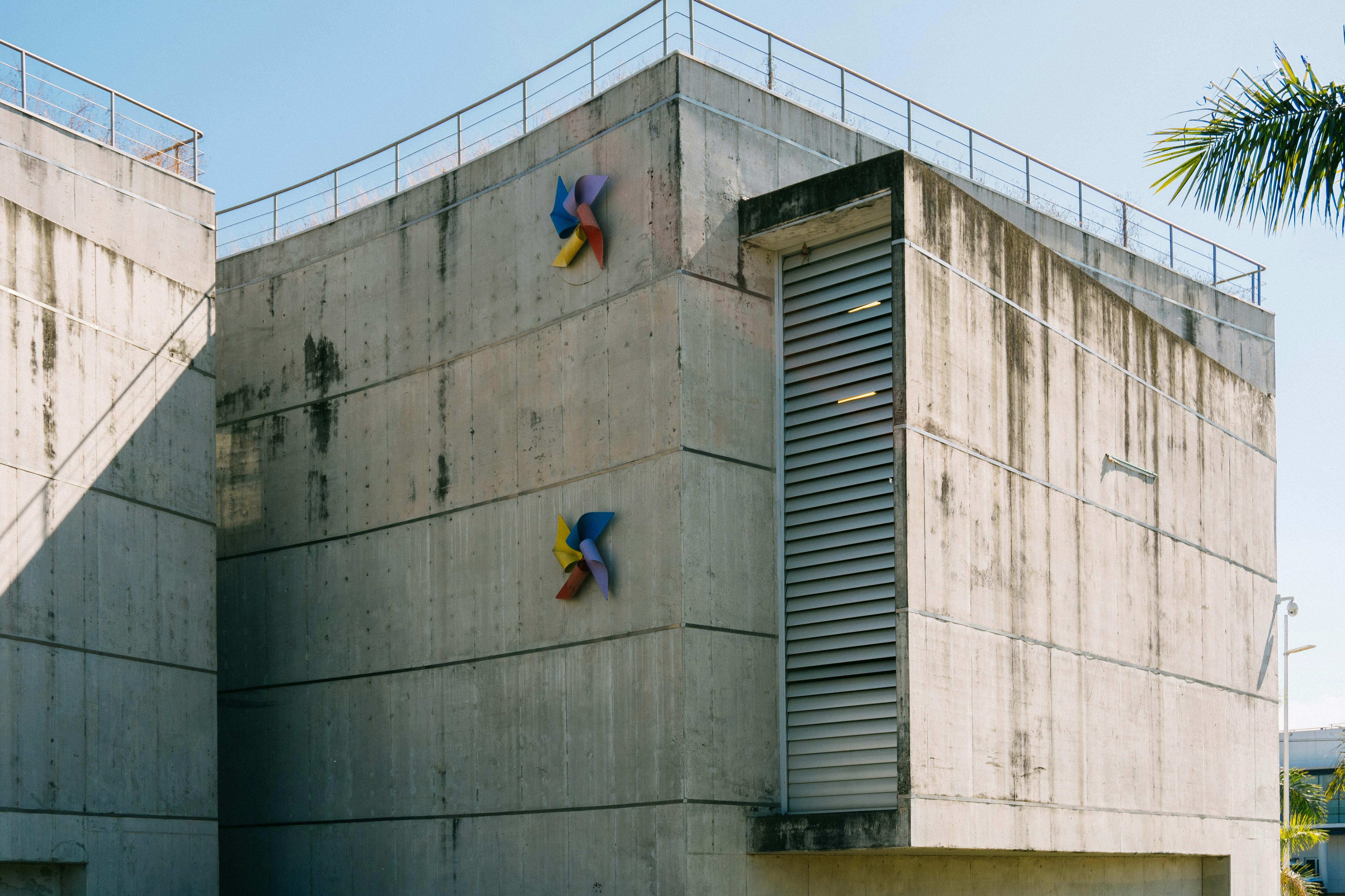 Two Colorful Bird Sculptures Adorning a Brutalist Concrete Facade