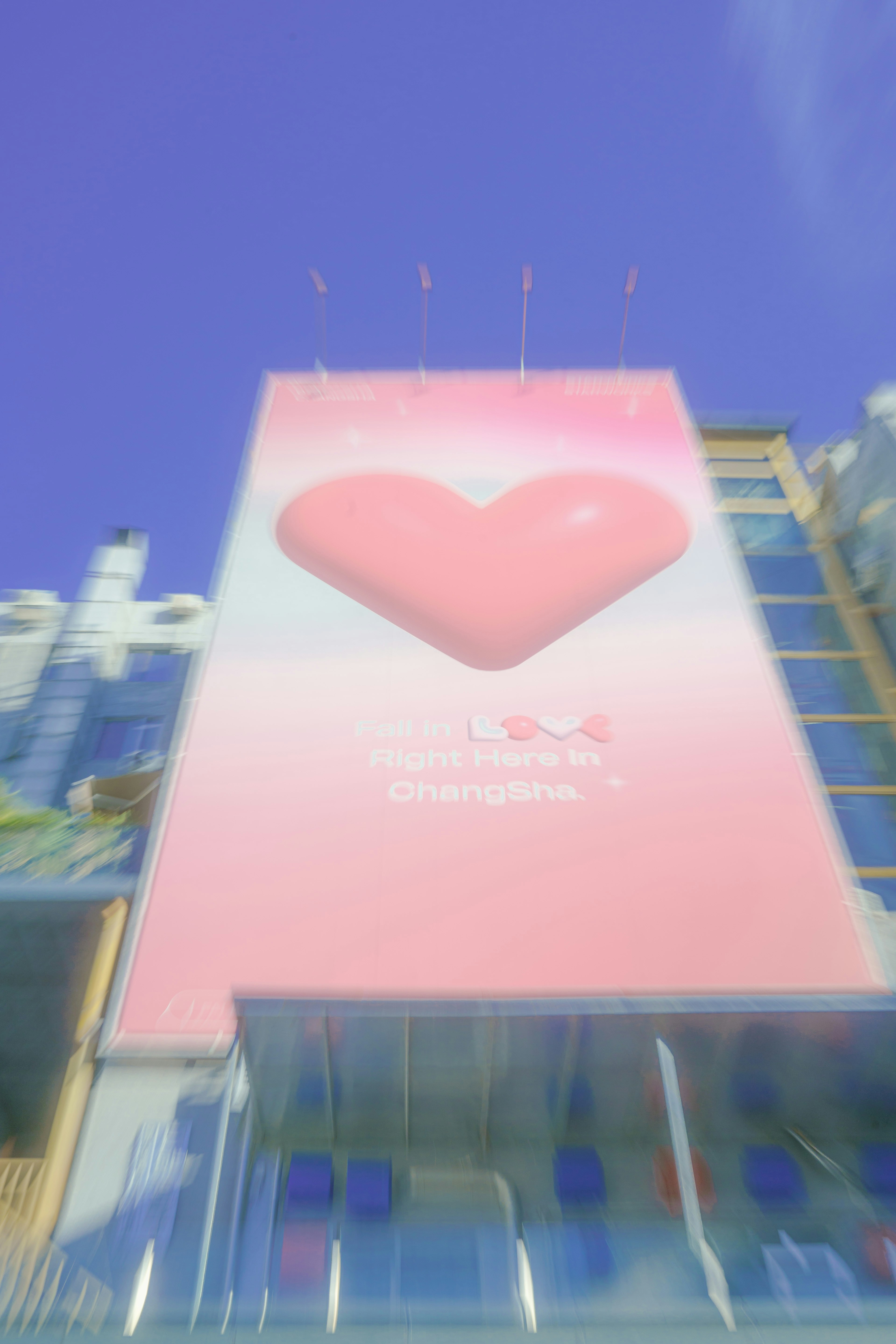 Blurred Pink Heart Banner Hanging Over a Glass City Block