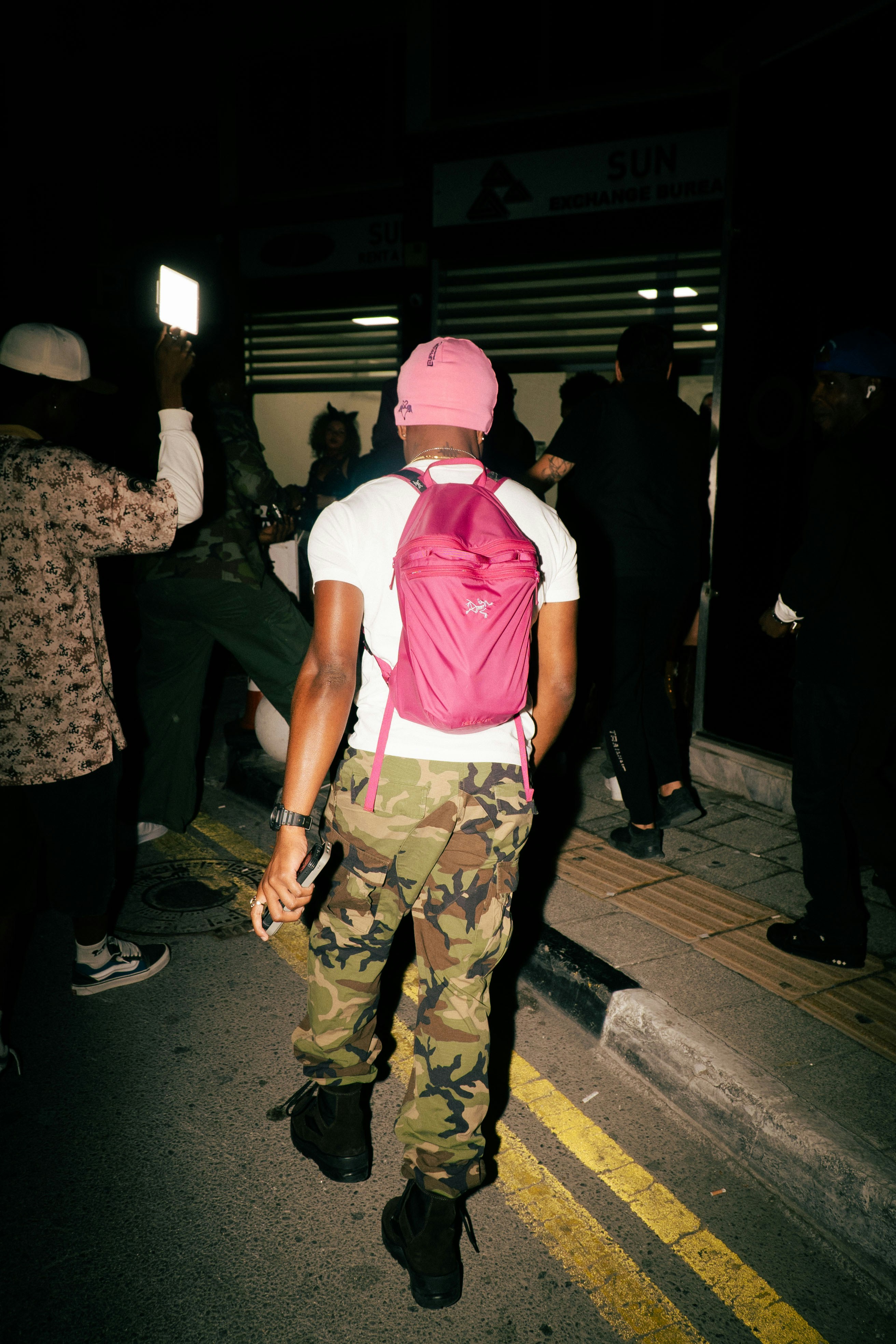 Midnight Brights: Pink Backpack Cutting Through the Night Crowd