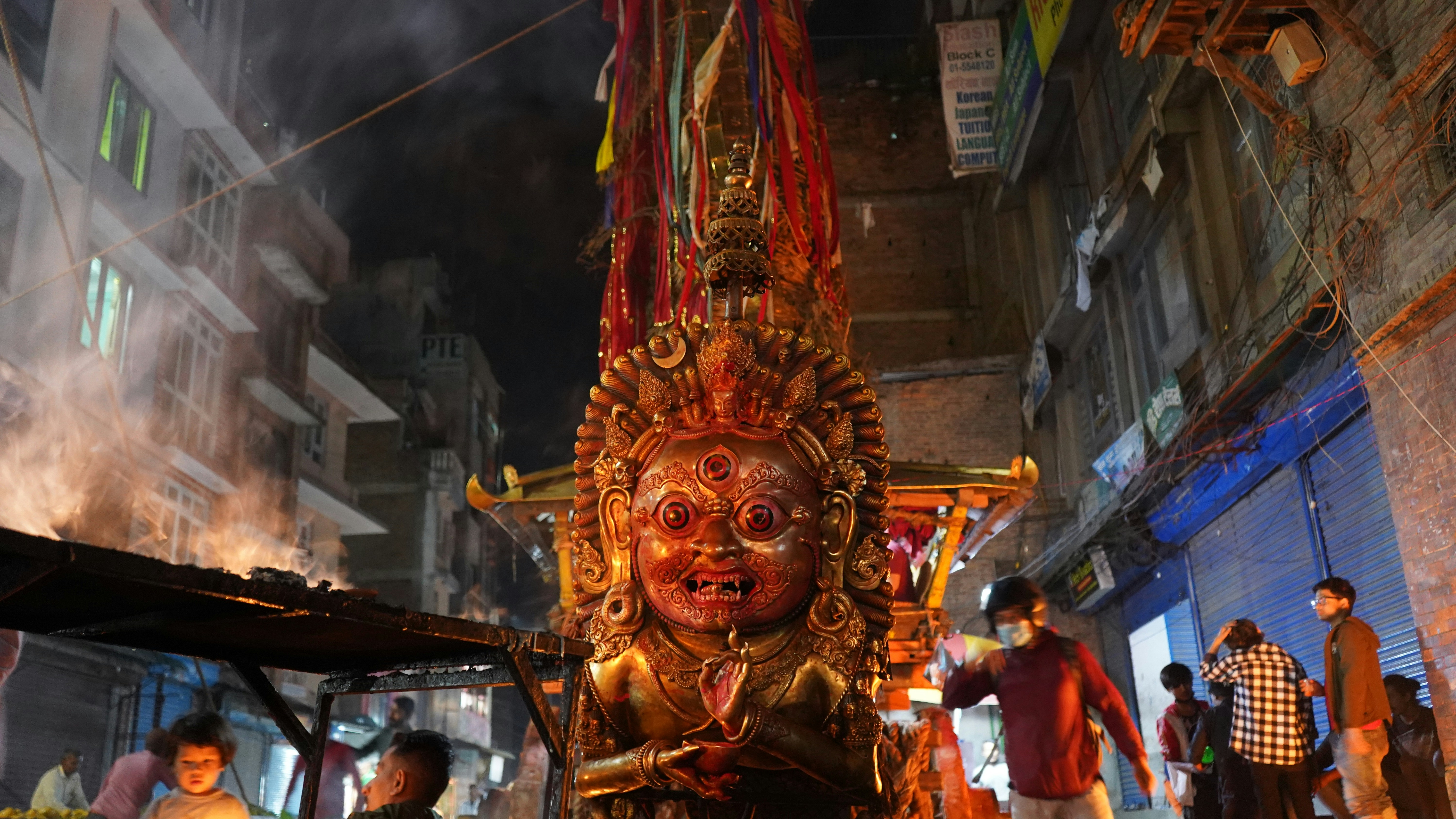 Gilded Deity Leads a Smoke-Filled Nighttime Street Procession