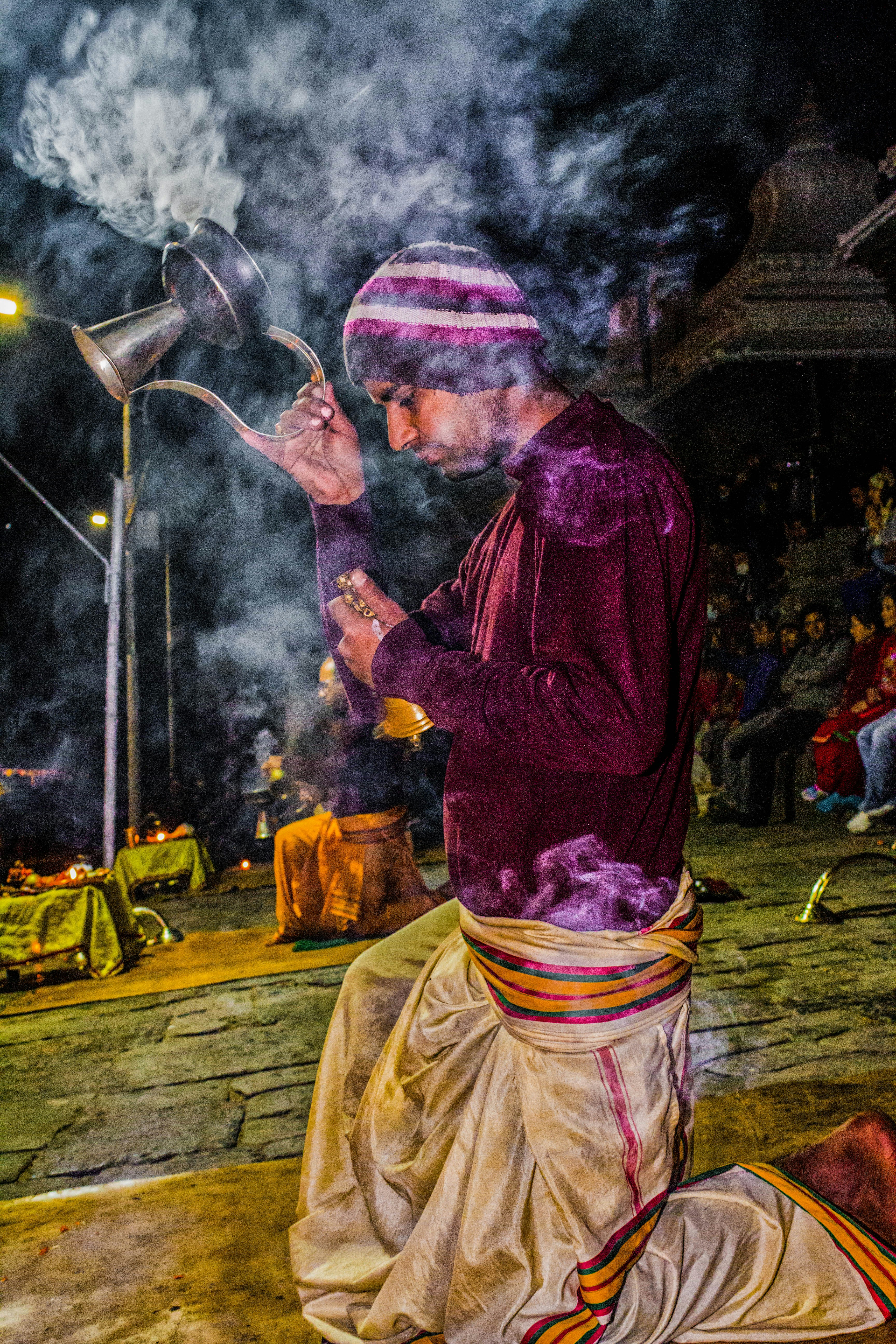 Night Aarti in Smoke: A devotee tends sacred flames under a smoky glow