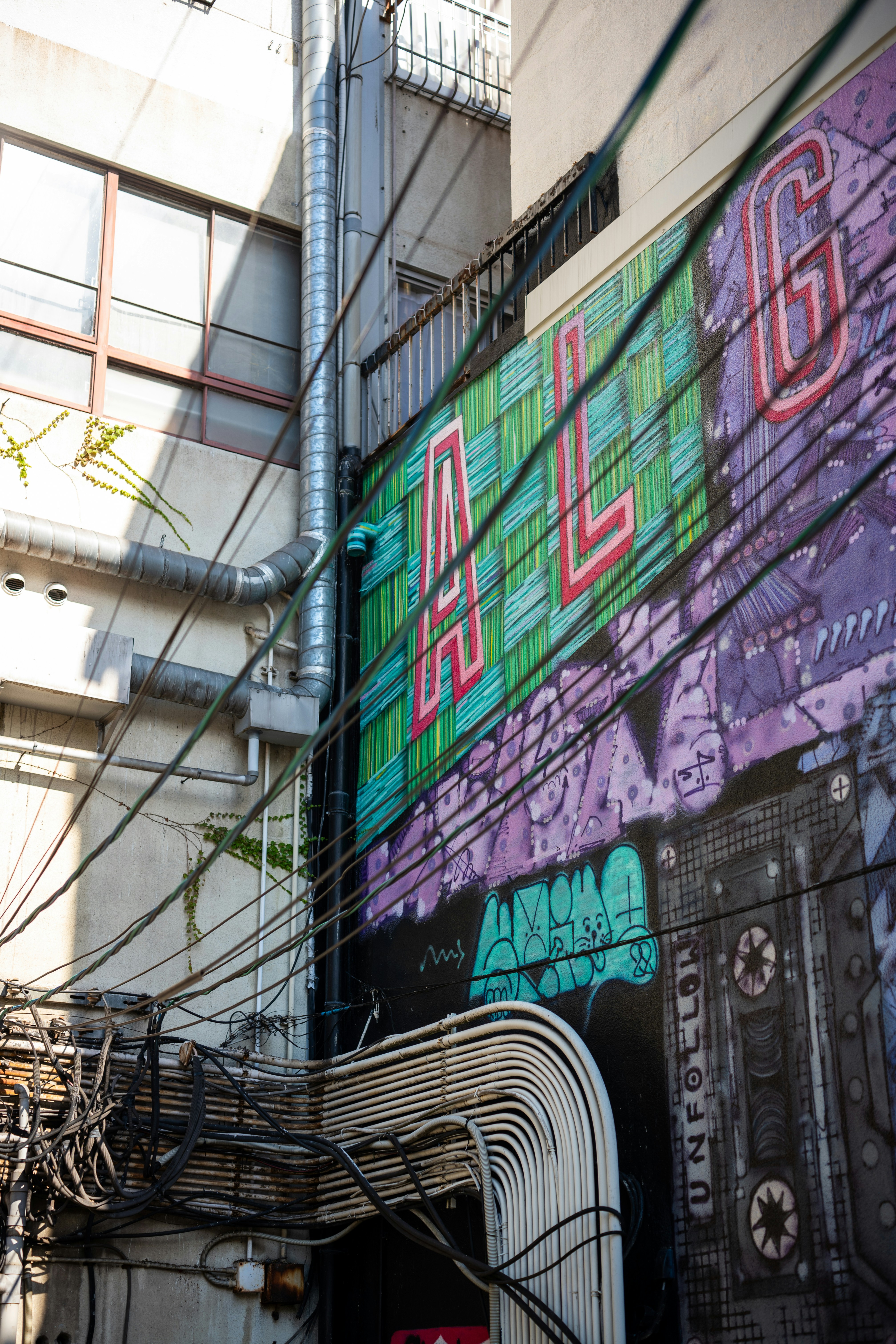 Neon Graffiti Wall Framed by a Tangled Web of Cables in an Alley