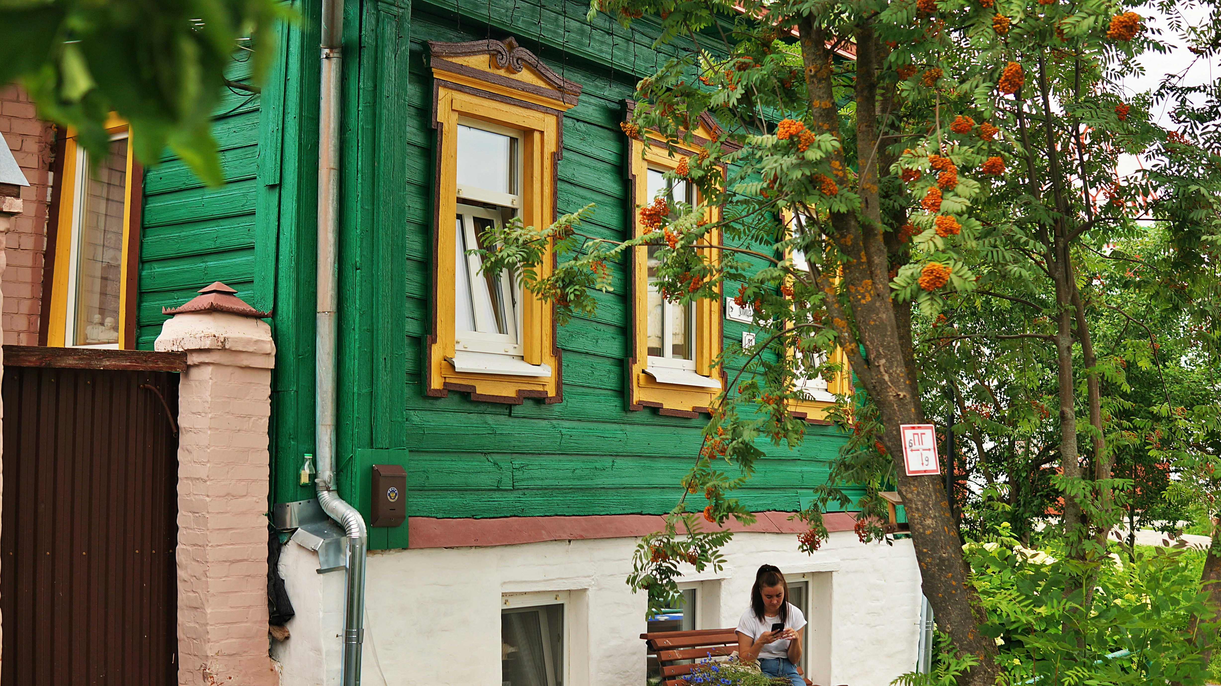 Verdant Facade Portrait: Green Walls, Golden Window Frames, and a Quiet Bench Moment