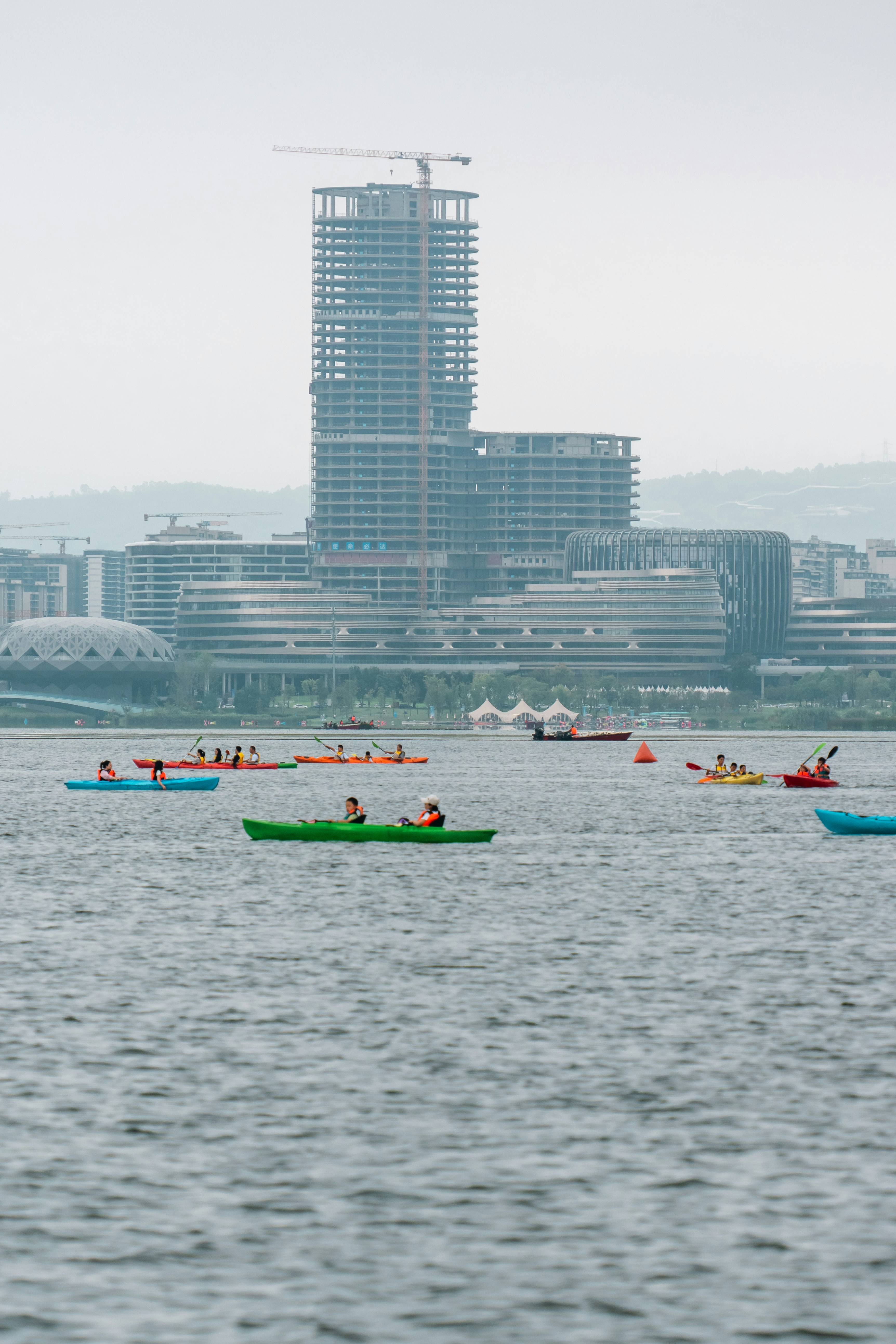 Green Kayak in a Quiet Waterfront Beneath a Rising City Skyline