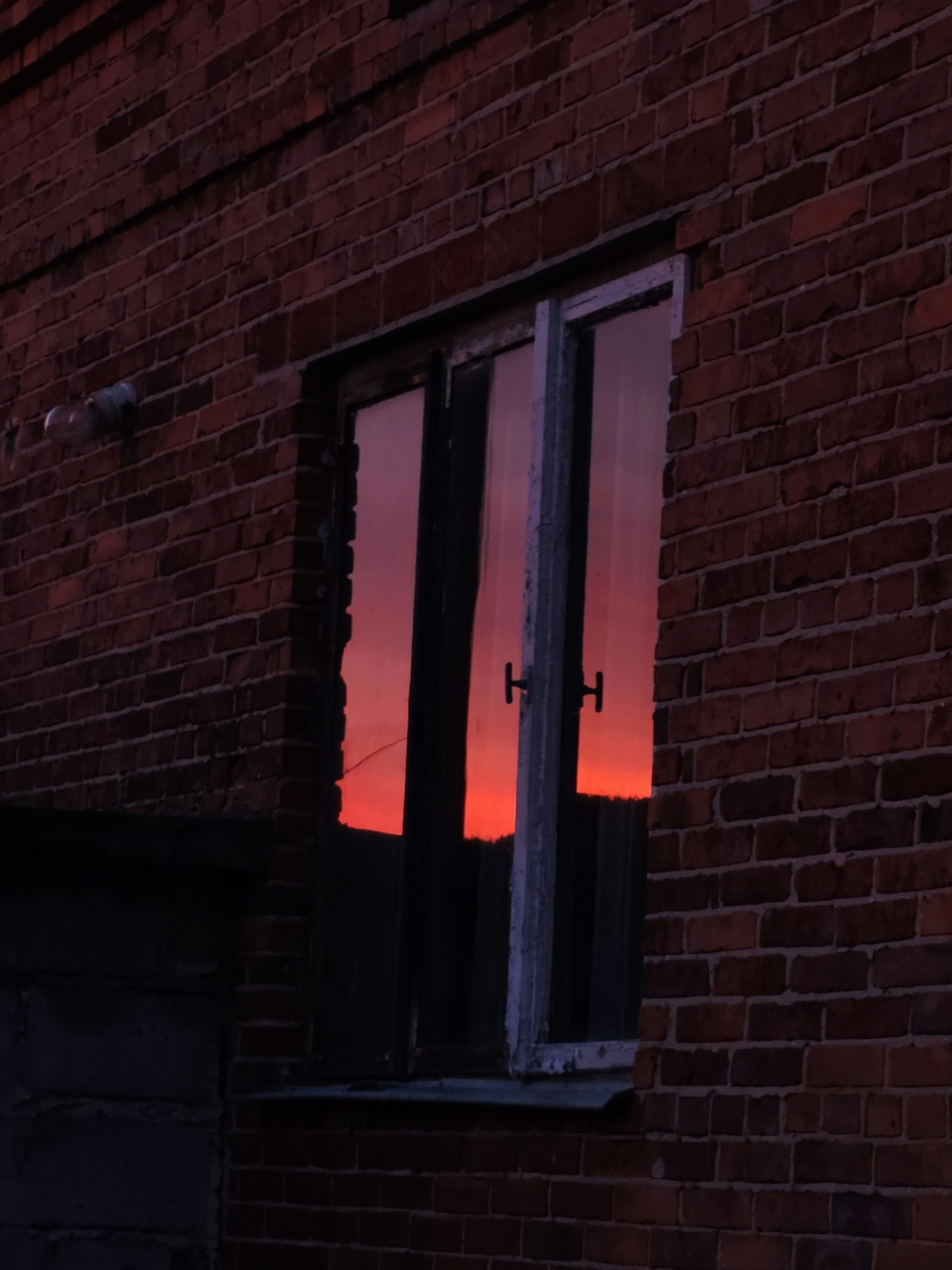 Crimson Window Reflection on Red Brick at Twilight