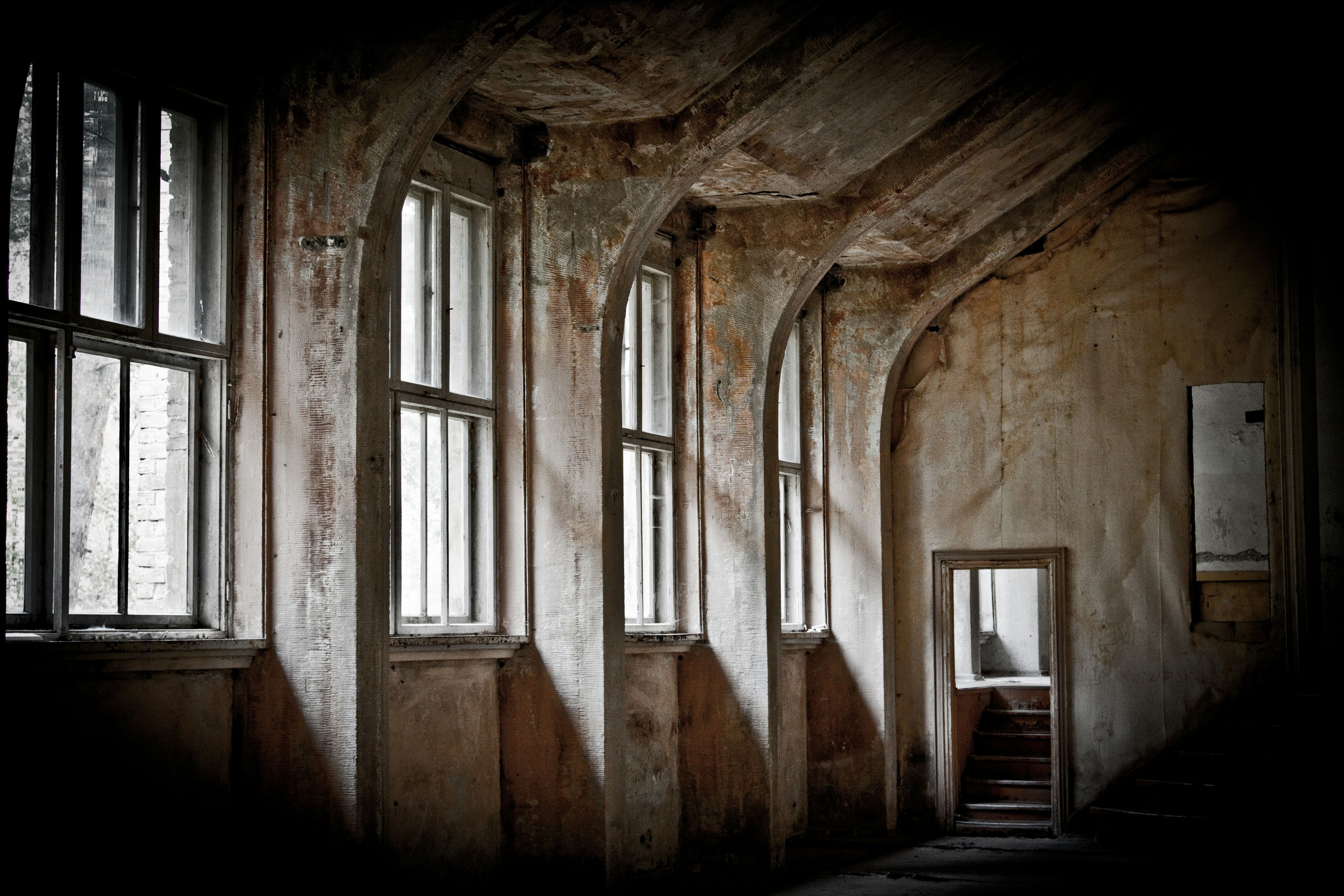 Sunlit Arches and a Hidden Staircase in a Ruined Interior
