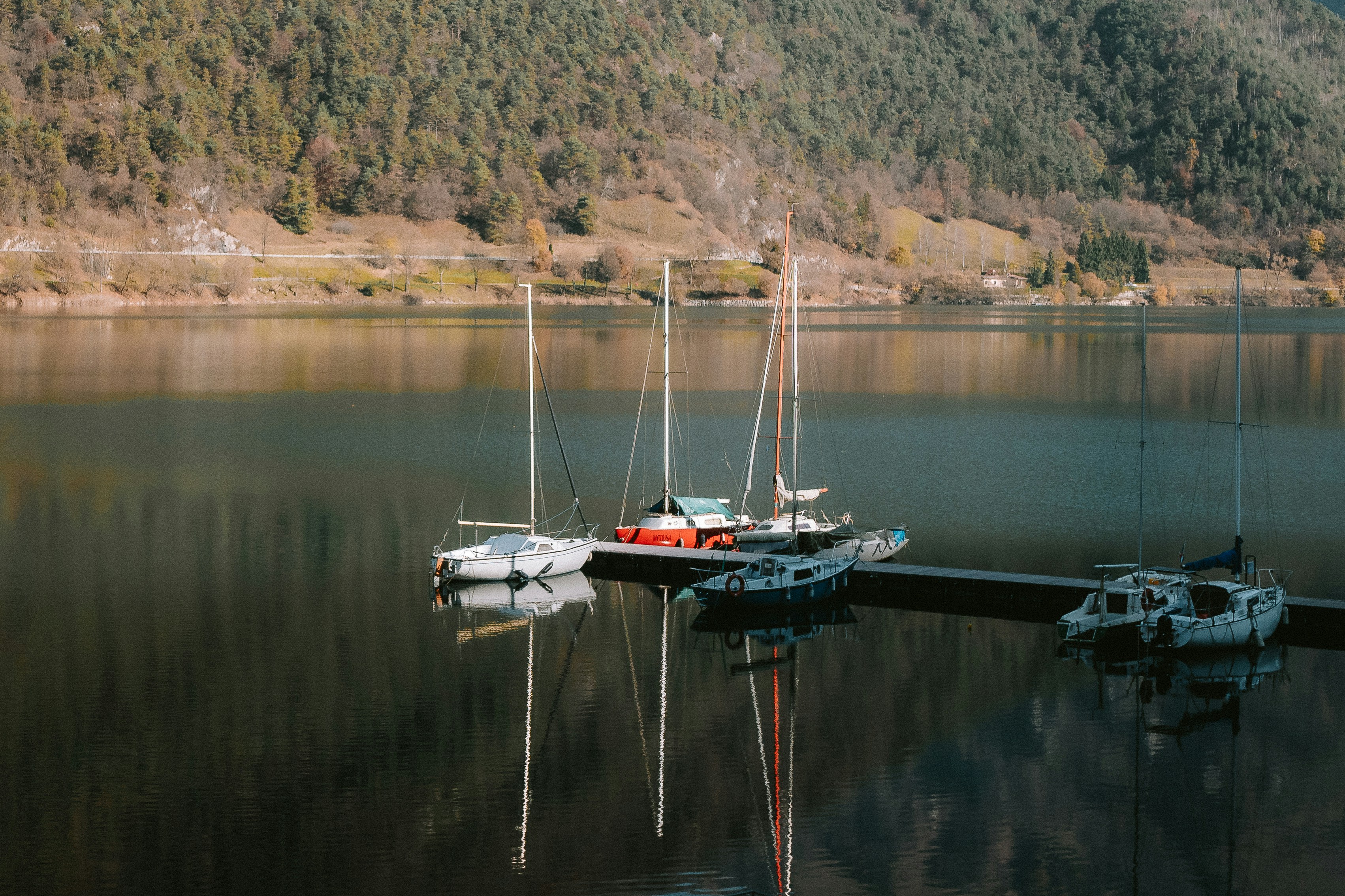 Red Hull and Silent Sails Reflect on a Glassy Lake