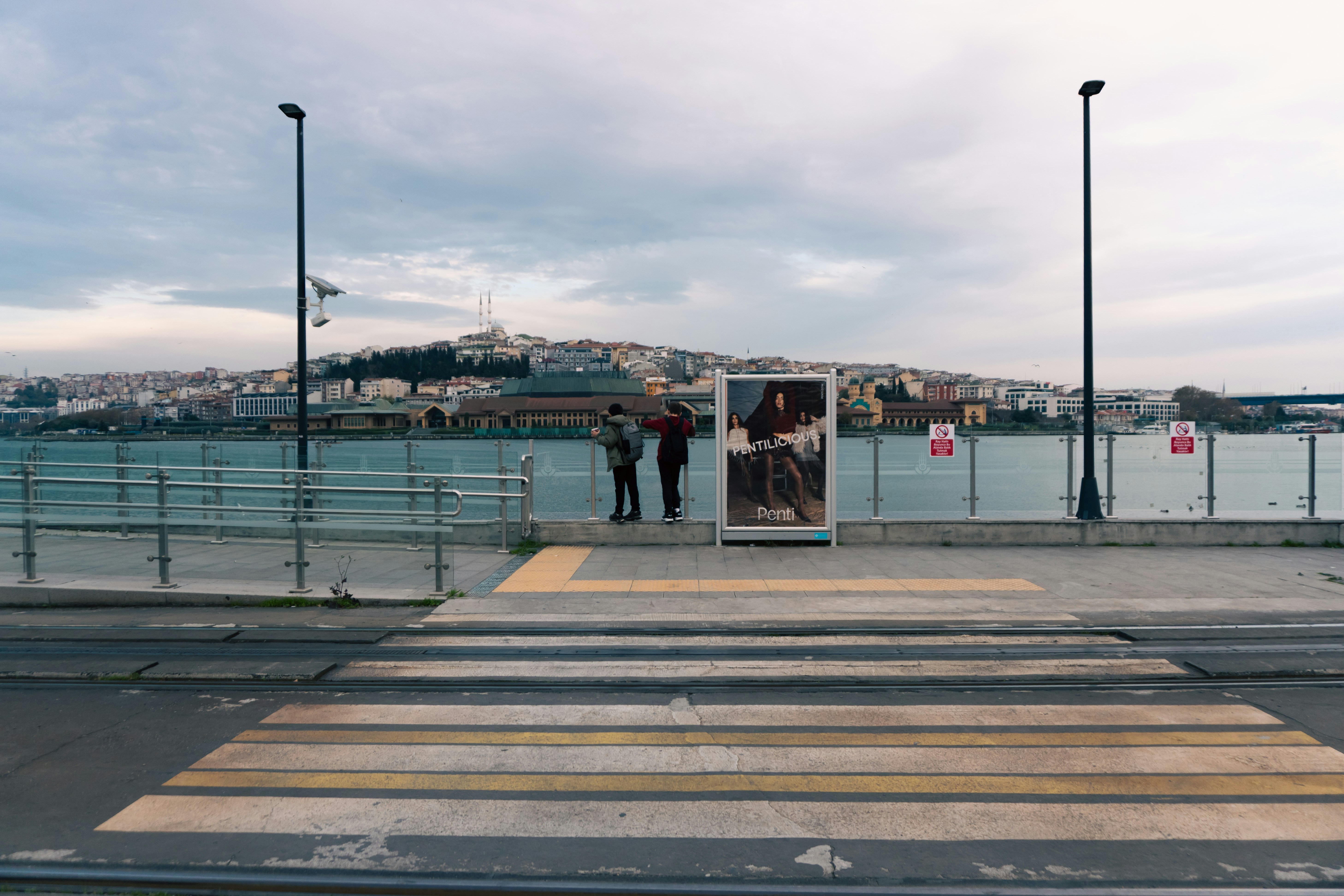 Harbor Promenade Encounter: Two Viewers Frame a City Across Calm Waters
