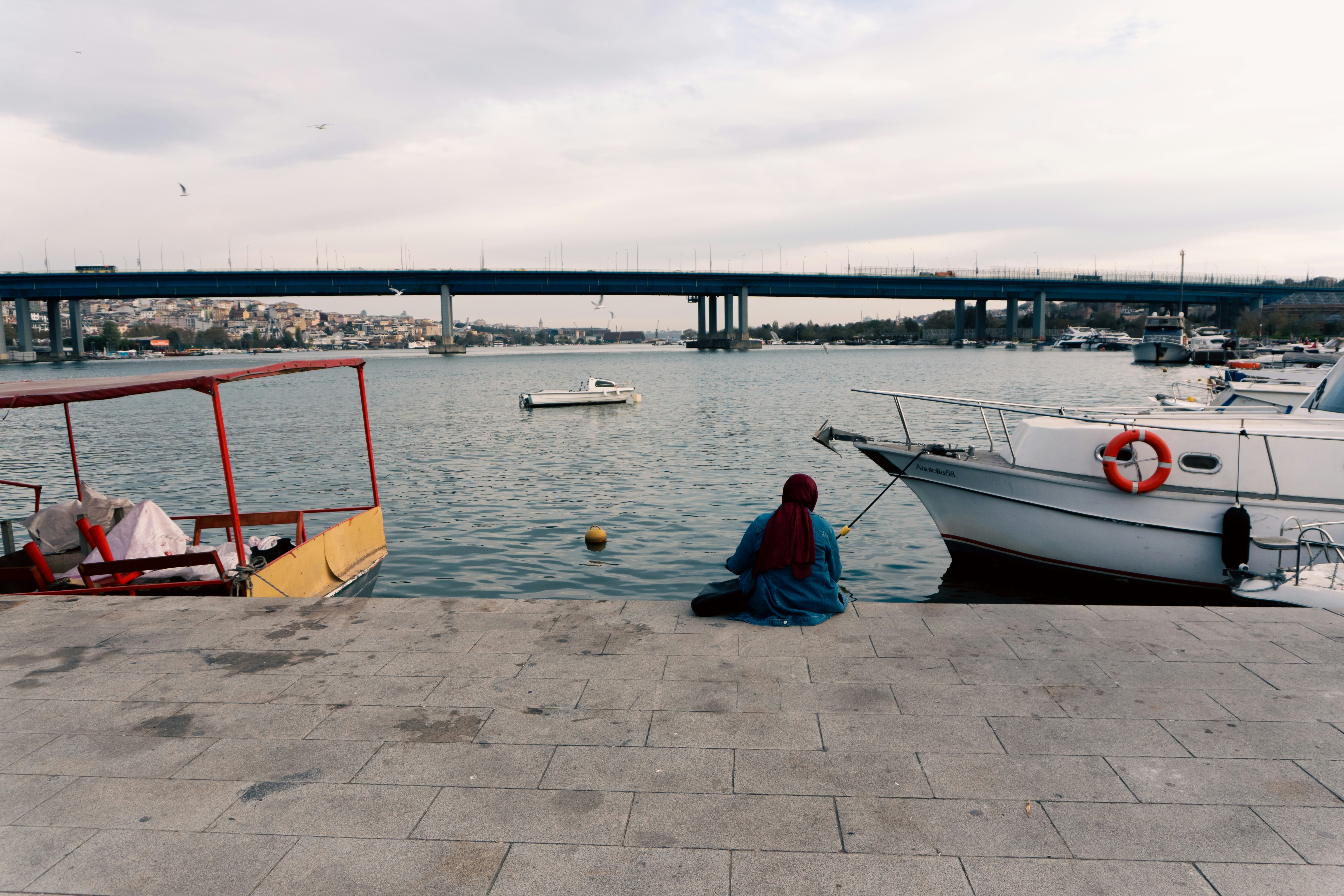 Blue-clad Figure at the Harbor: Stillness by Boats and Bridge