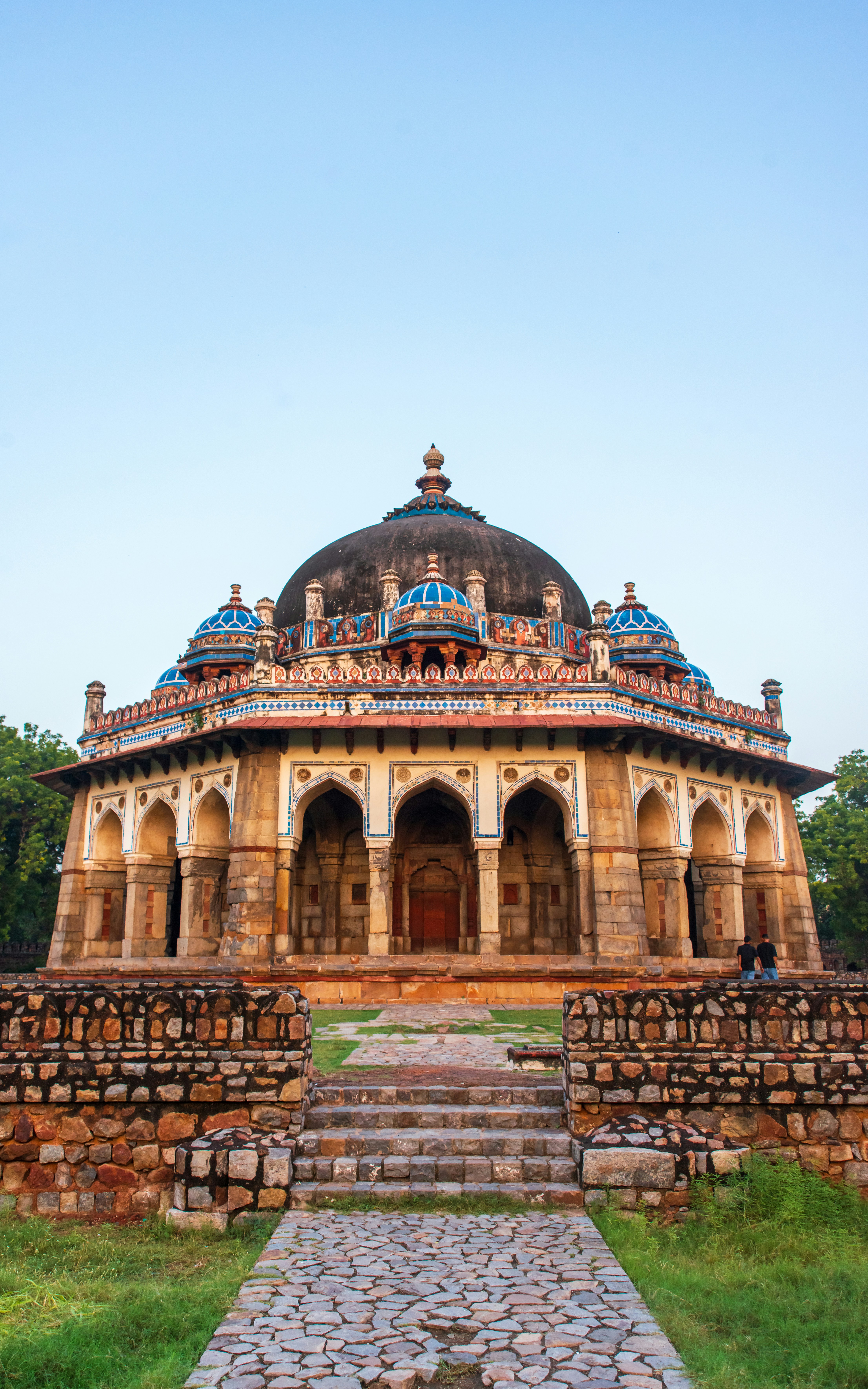 Isa Khan's Tomb, located within the Humayun's Tomb Complex, is an octagonal mausoleum built in 1547–1548 AD, predating the main tomb. Constructed primarily of grey quartzite and red sandstone, it showcases a transitional Lodi architectural style. The tomb features a deep veranda with triple arches on each of its eight sides, intricate stone lattice screens (jalis), and a central dome adorned with canopies and glazed blue, green, and turquoise tiles.