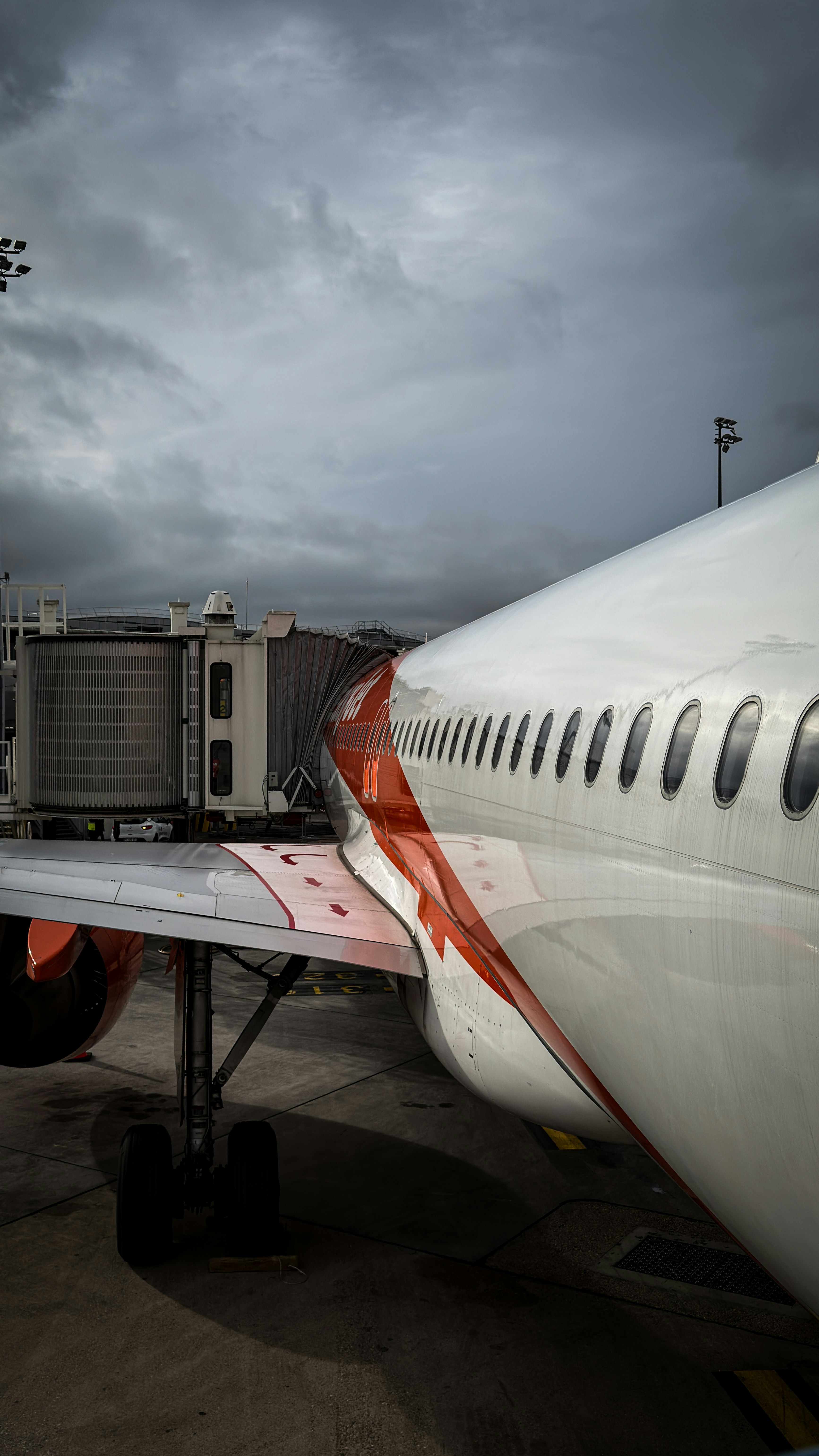 Airplane connected to a jet bridge under cloudy sky