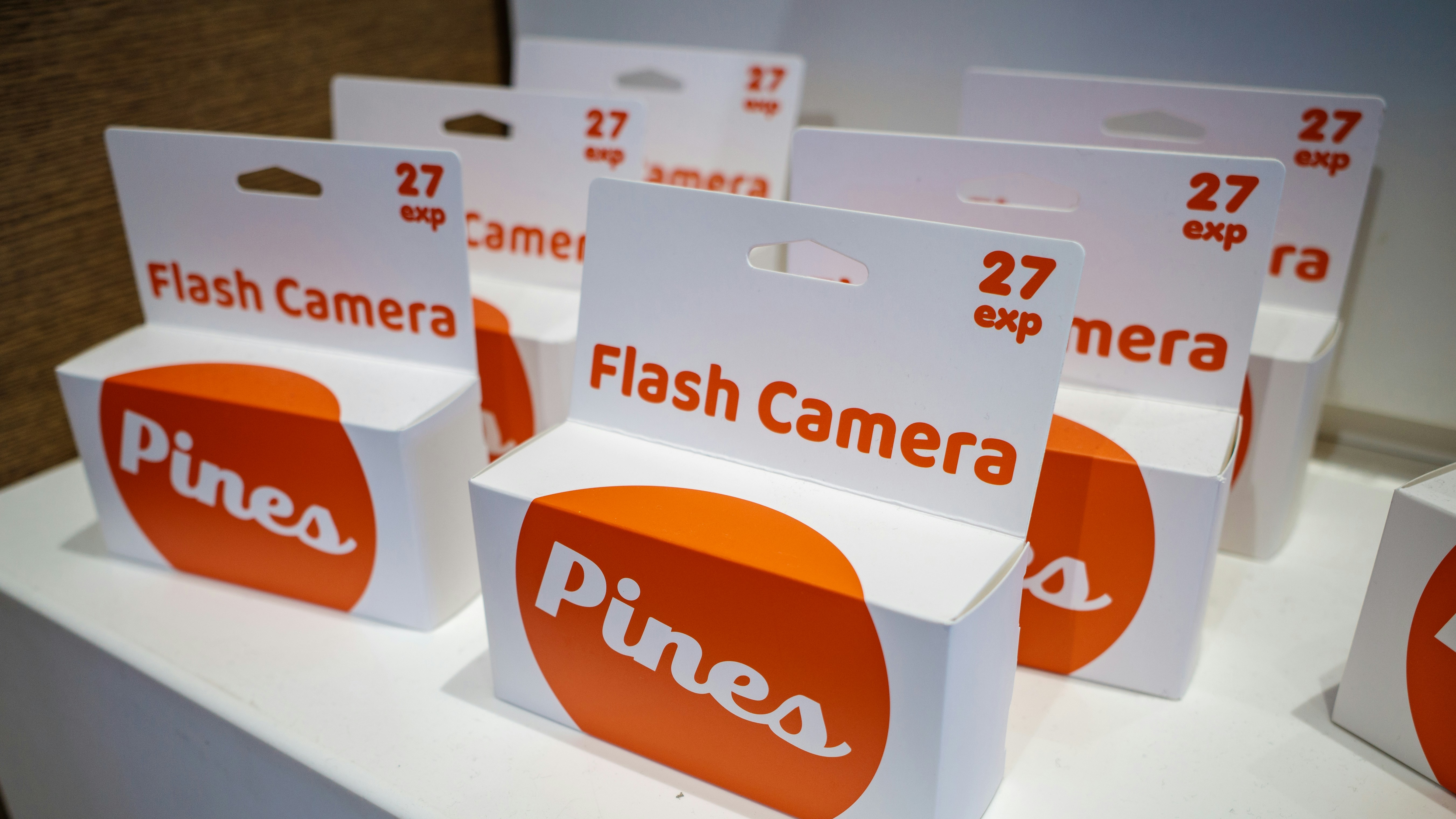 Orange Circles Amid White Shelves: Pine's Flash Camera Boxes