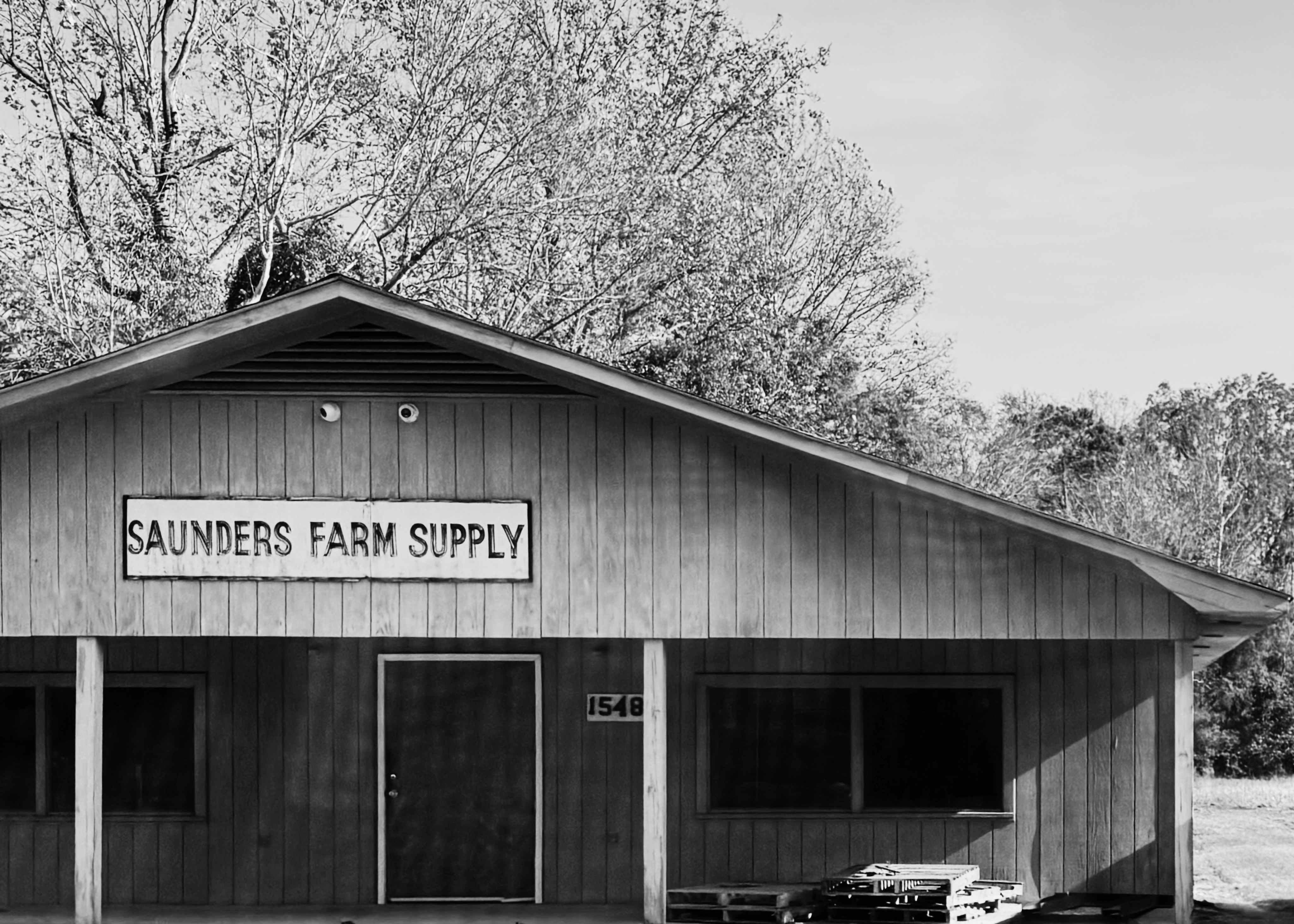 Saunders farm supply building with trees in background photo – Free ...