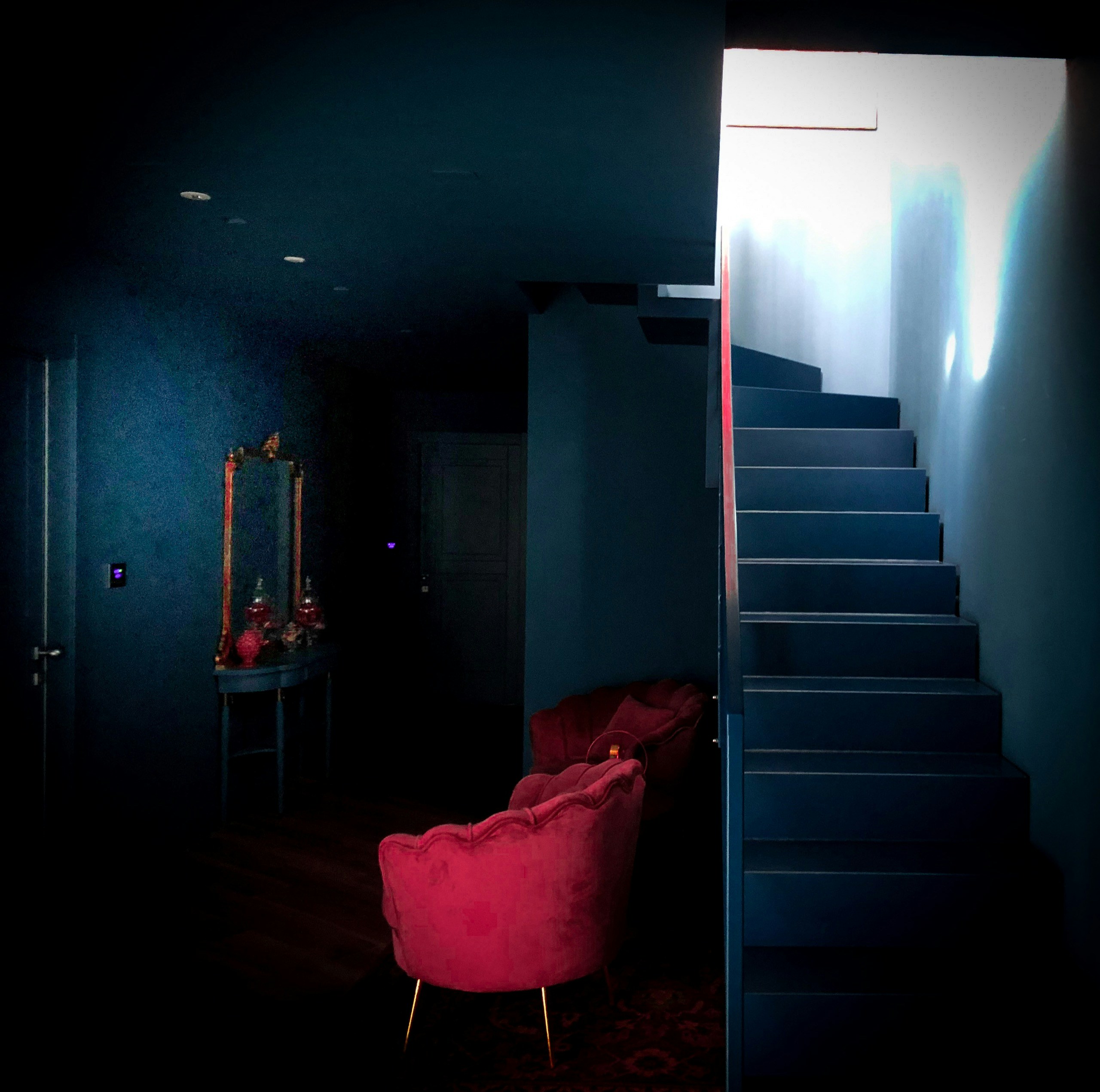 Red Velvet Chair Beneath a Moonlit Blue Staircase