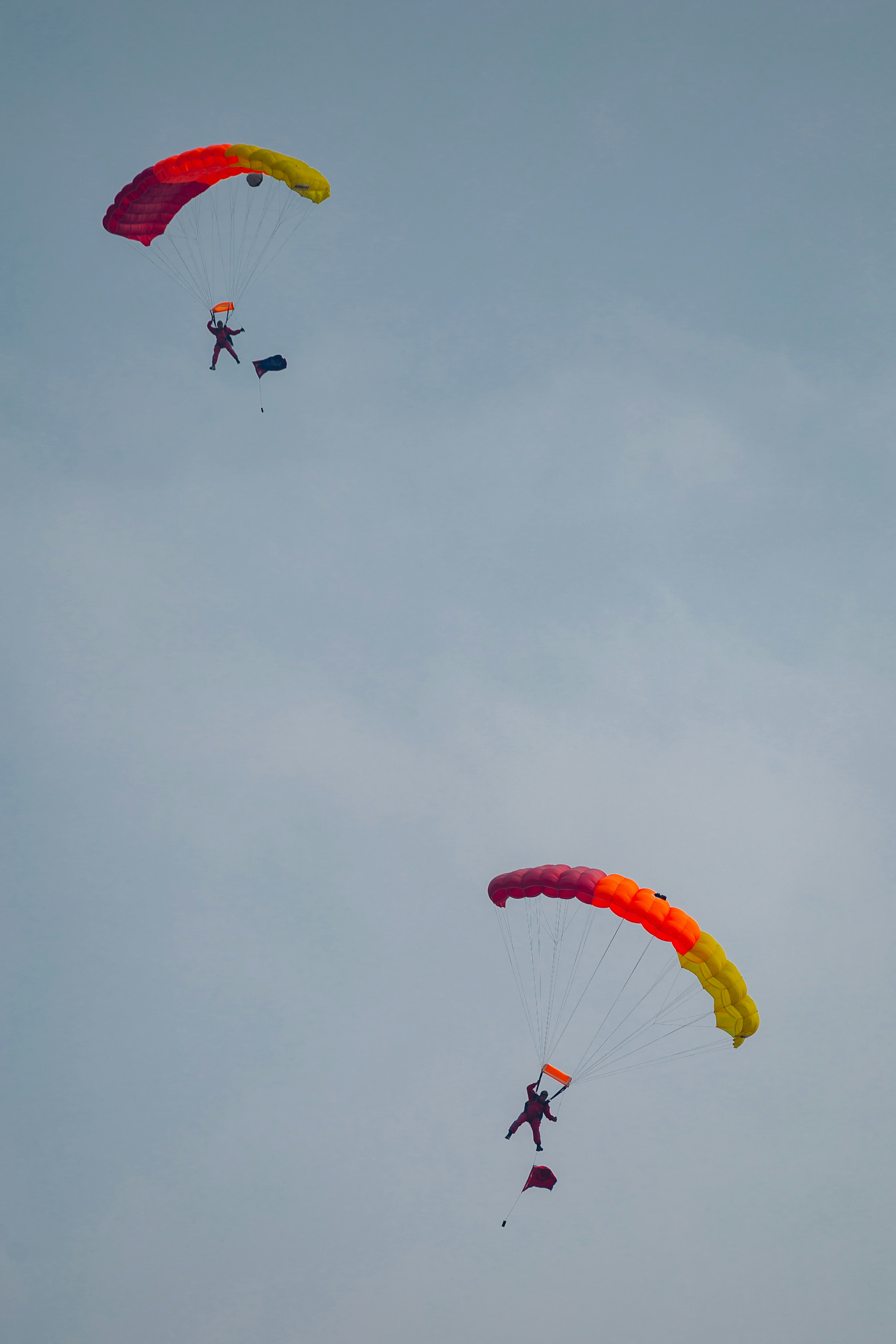 Duel in the Sky: Colorful Parachutes Against a Quiet Blue