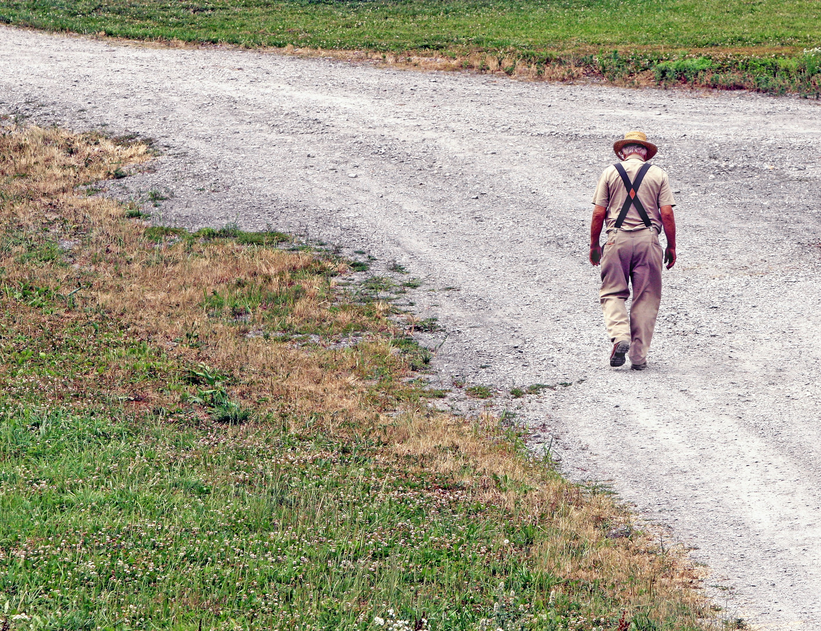 "Old Man on Road" --- A solitary man on a gravel road.