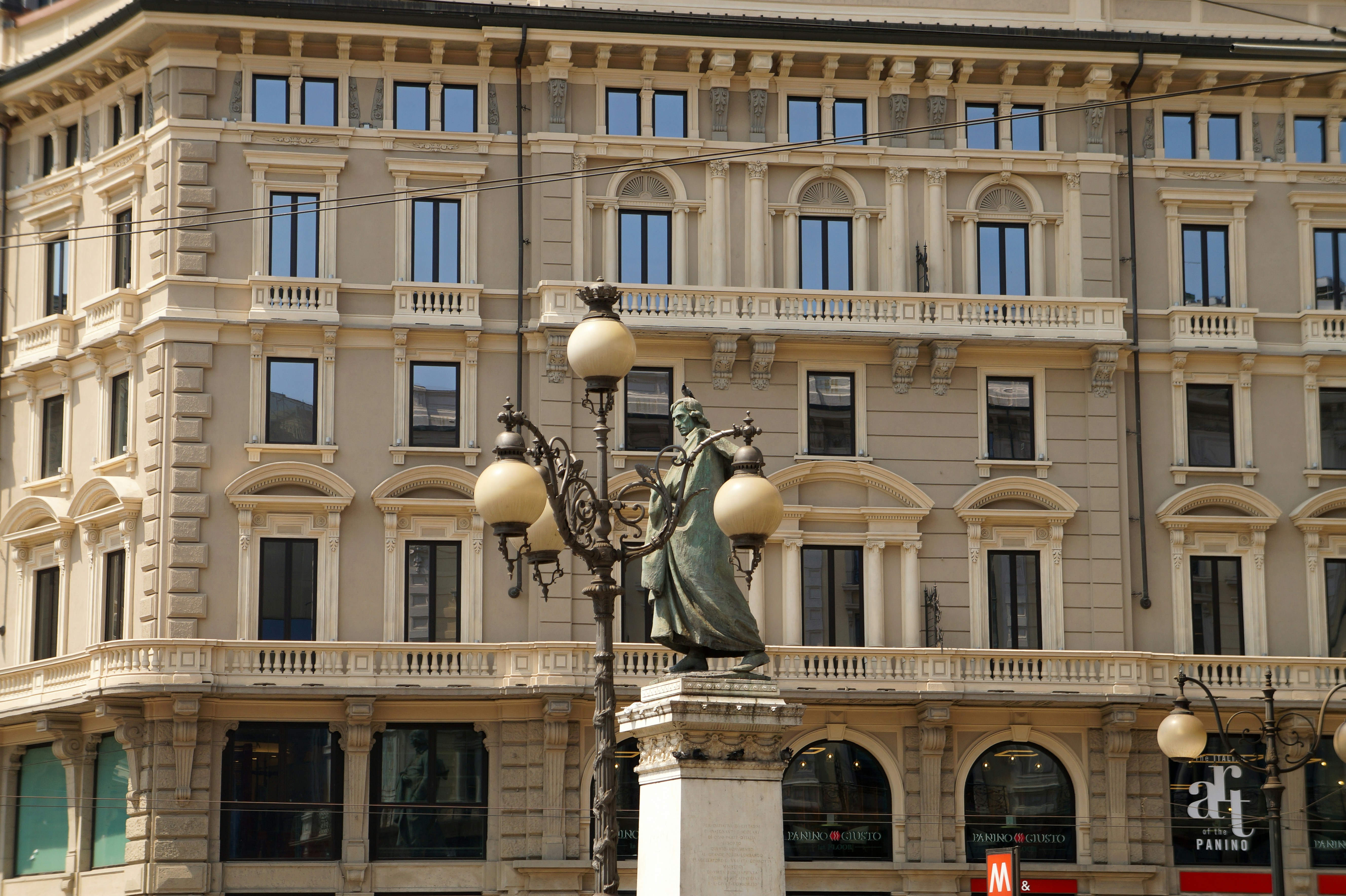 Bronze Sentinel Over Beaux-Arts Facade Beneath Orbed Street Lamps