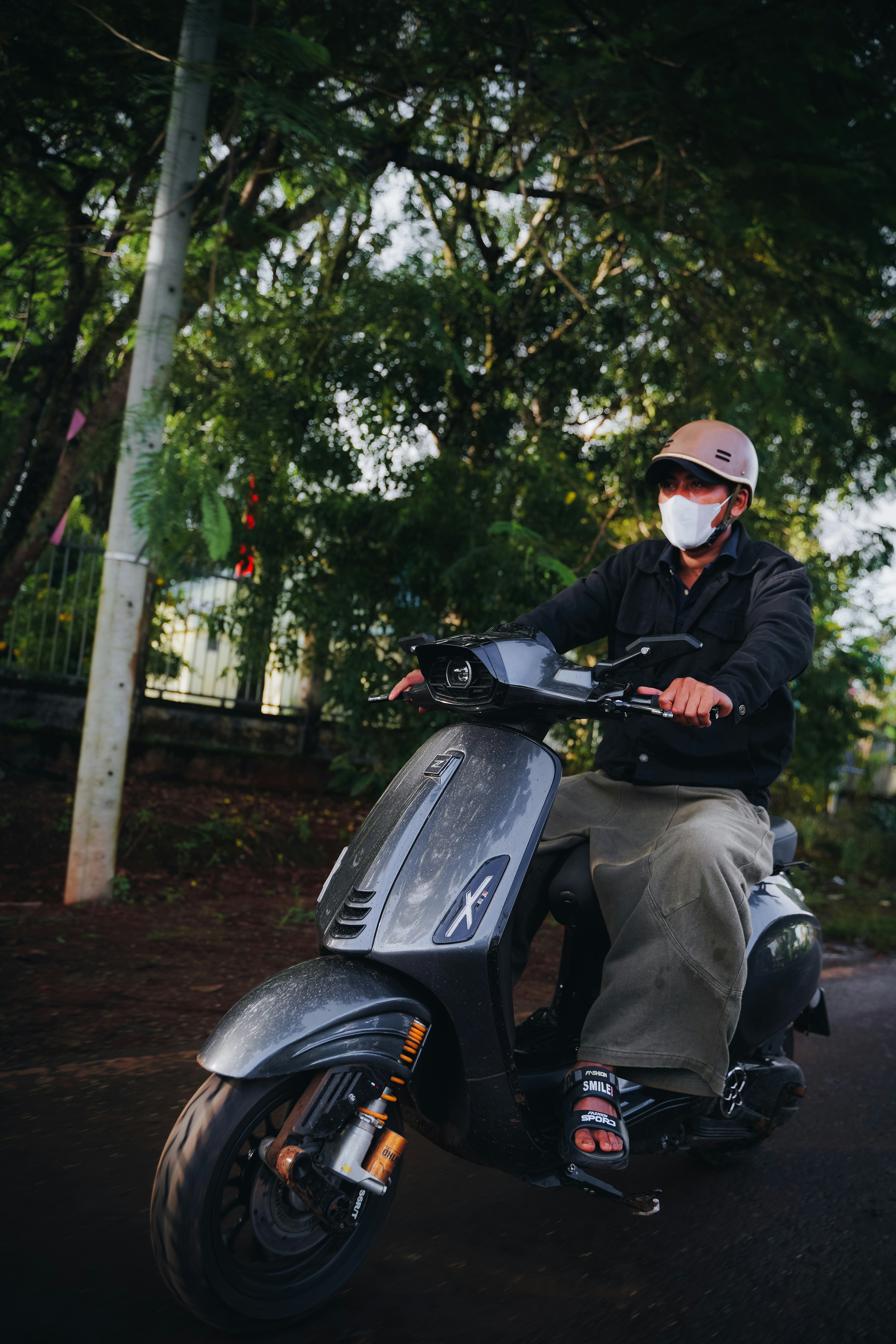 Masked Rider on a Gray Vespa in a Shaded Park