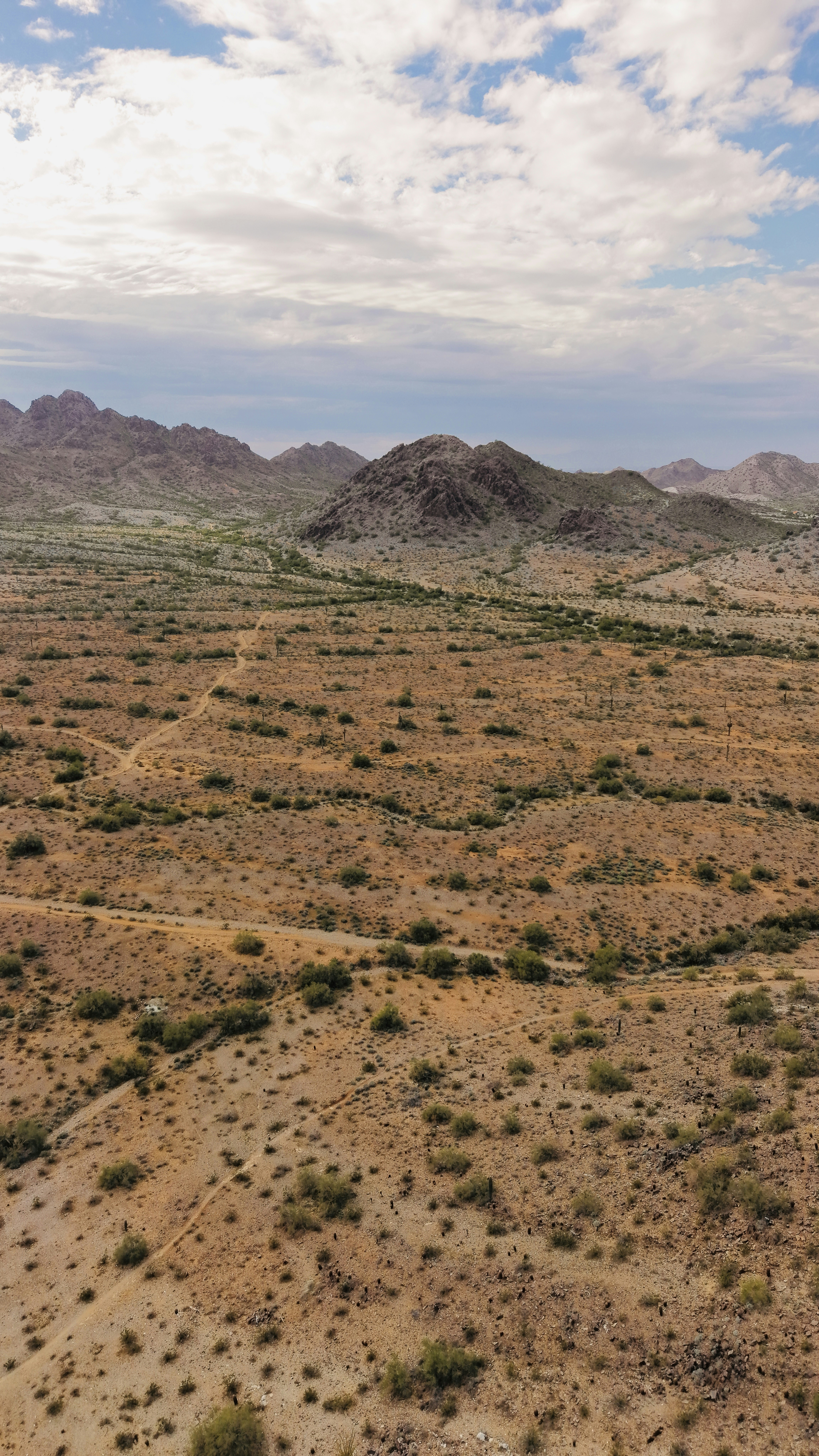 Arid landscape with mountains under a cloudy sky.