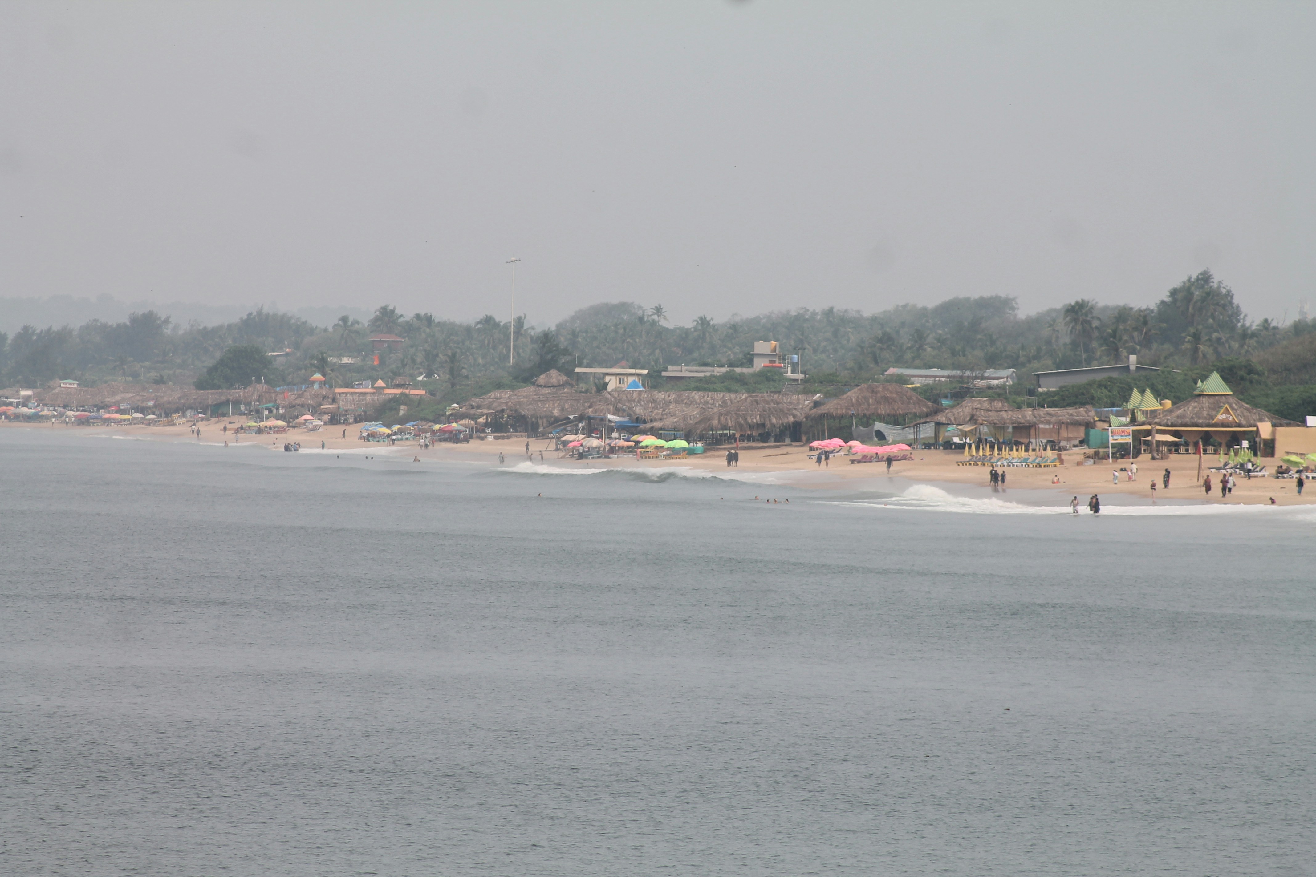 Beachfront Patchwork: Umbrellas and Distant Village on a Quiet Shore