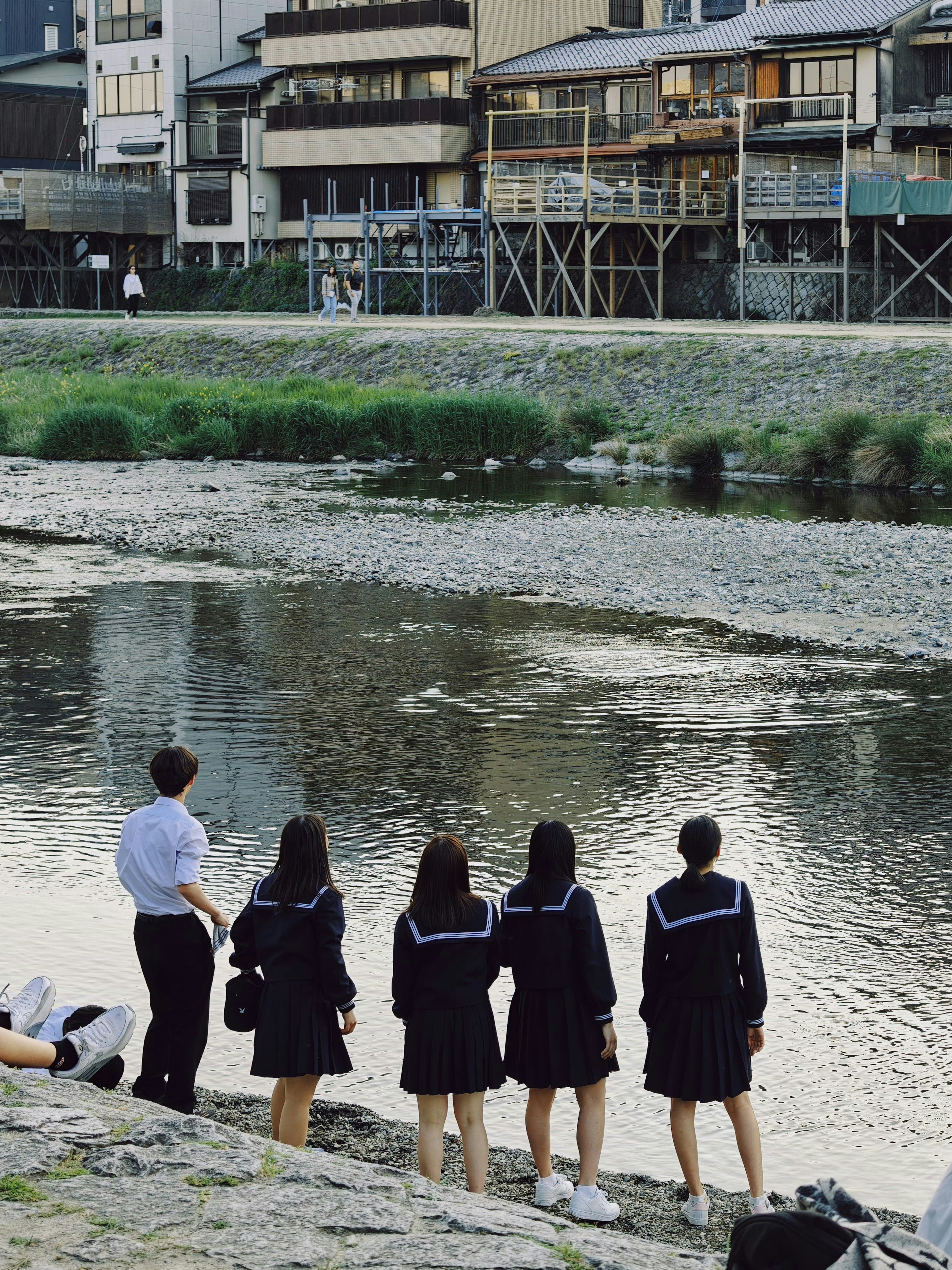Students in uniform by a river with buildings behind photo – Free ...