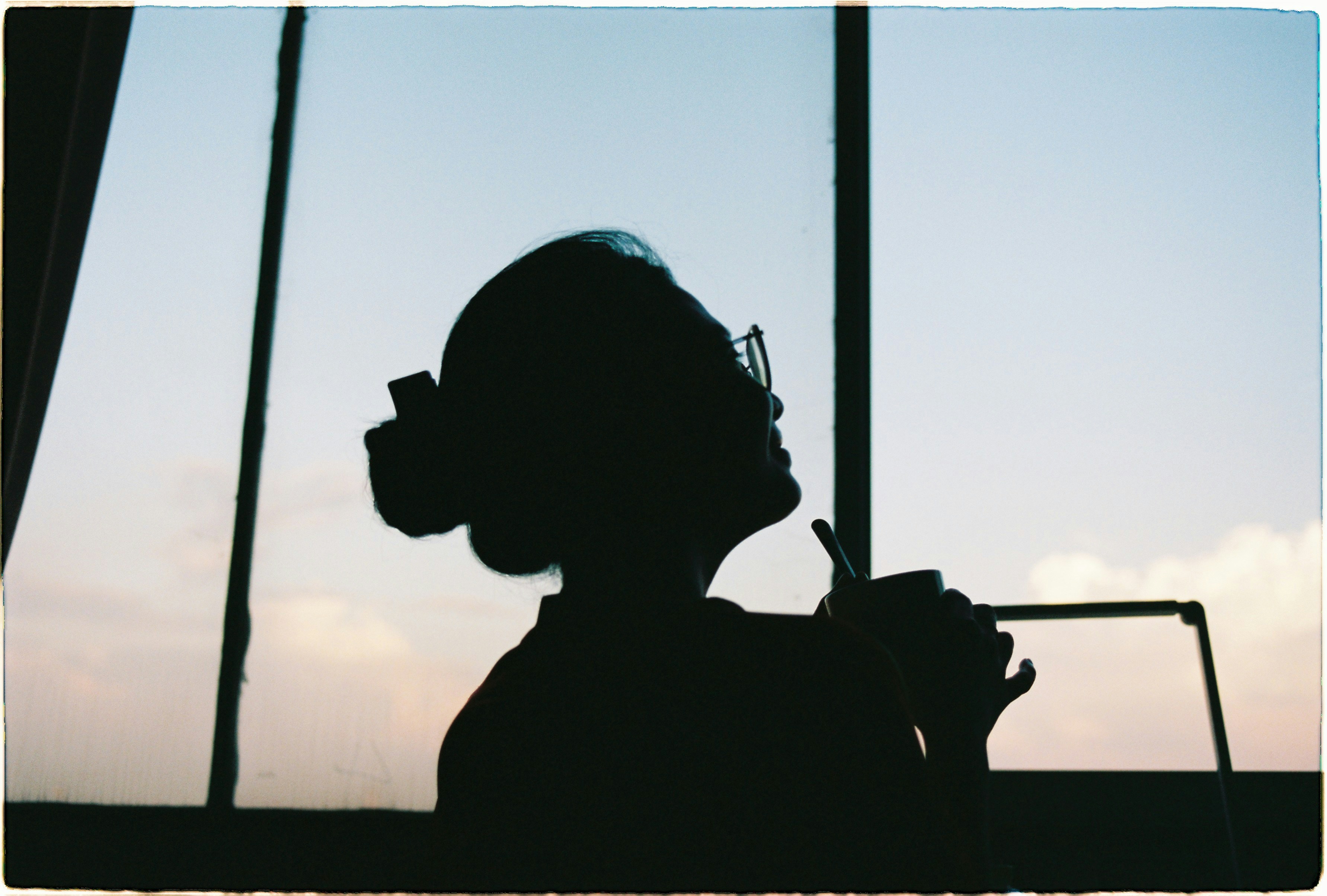 Silhouette at Dusk: A Quiet Sip by the Window