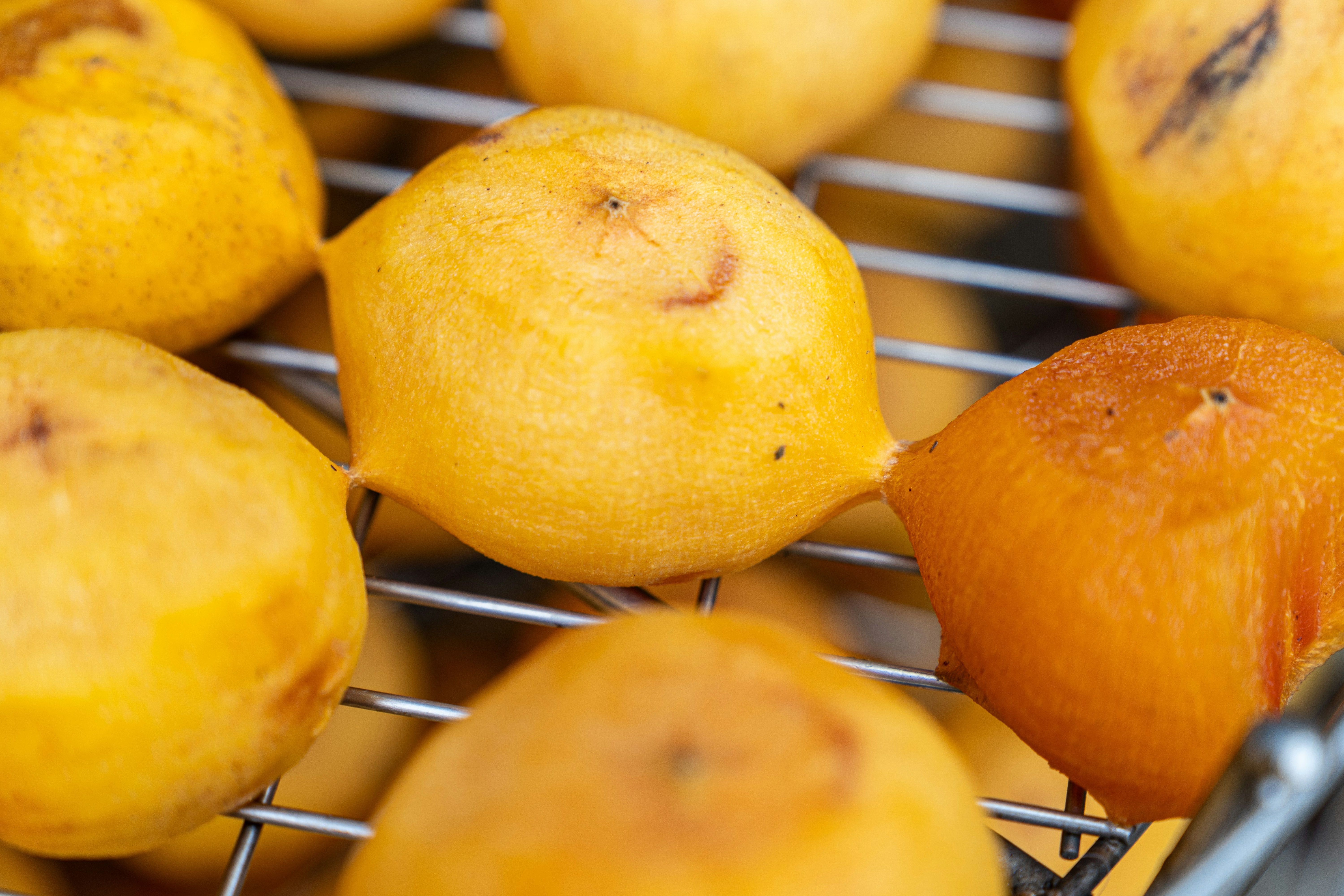 Zest on Stainless: Close-Up Lemons Draped Across a Wire Rack