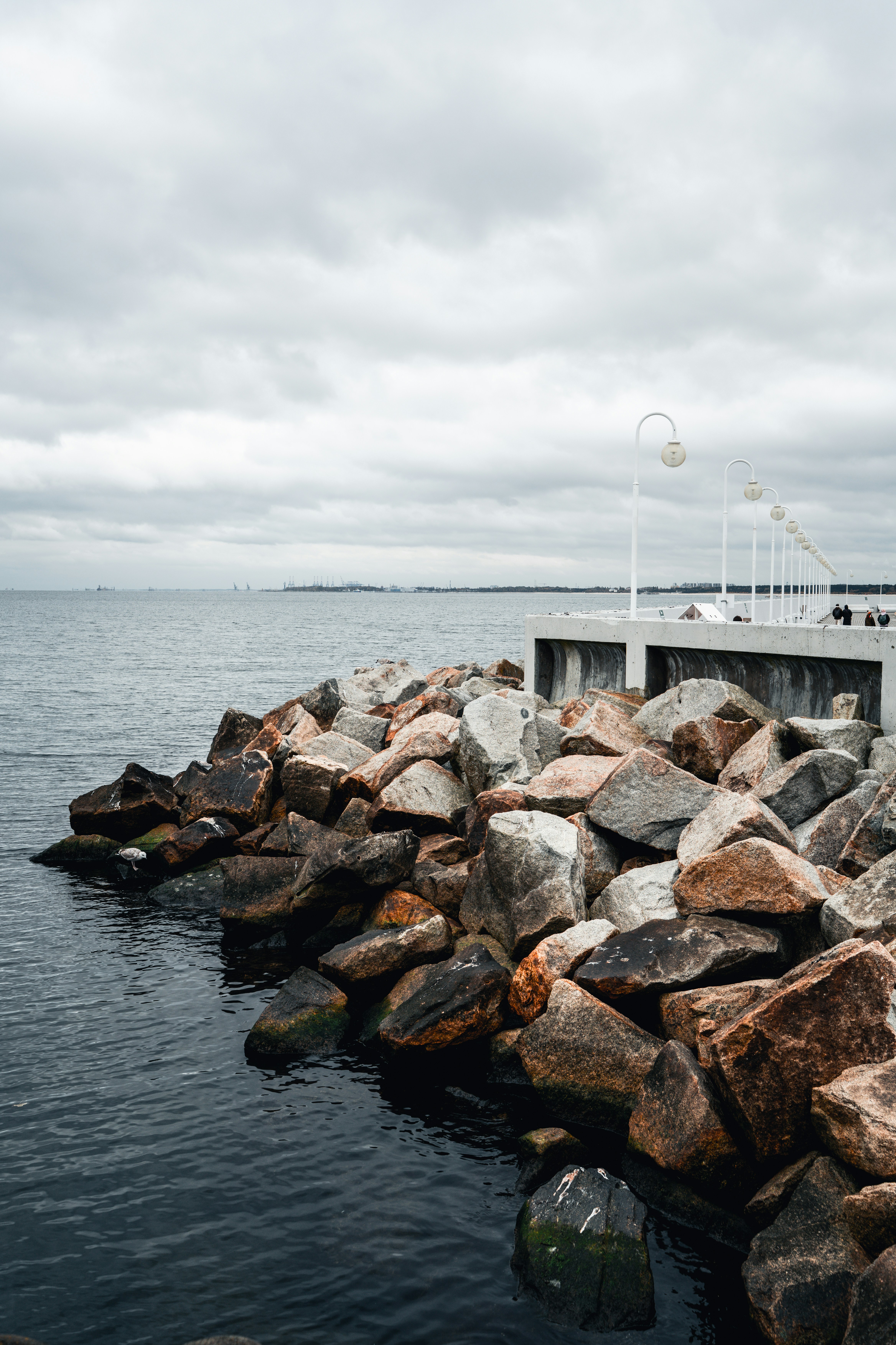 Stone Jetty under Overcast Light: A Rock Breakwater Reaching Toward the Pier