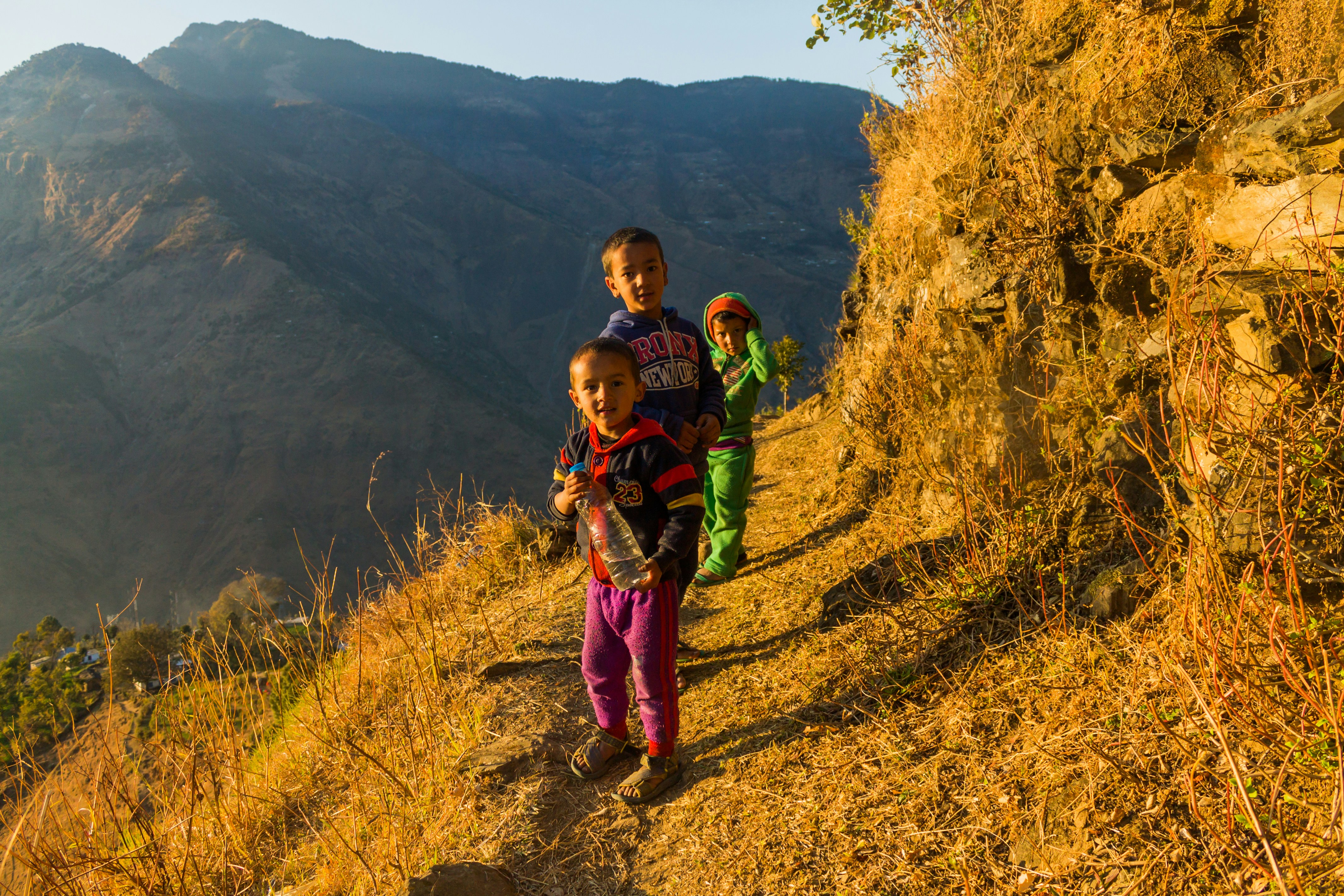 Golden Ridge Trek: Three Young Adventurers on a Cliffside Trail