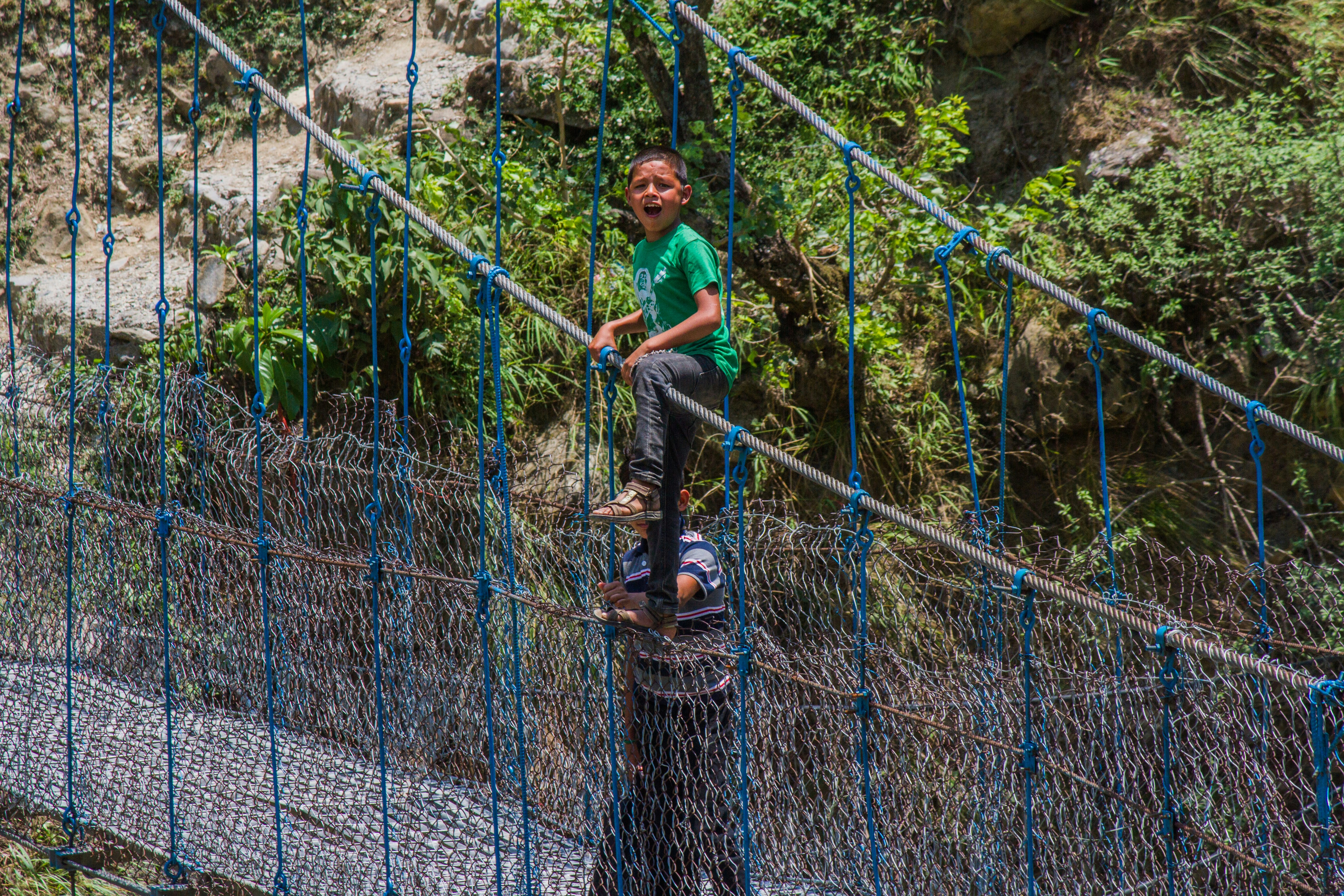 A young boy crosses a rope bridge over a gorge. photo – Free Child ...