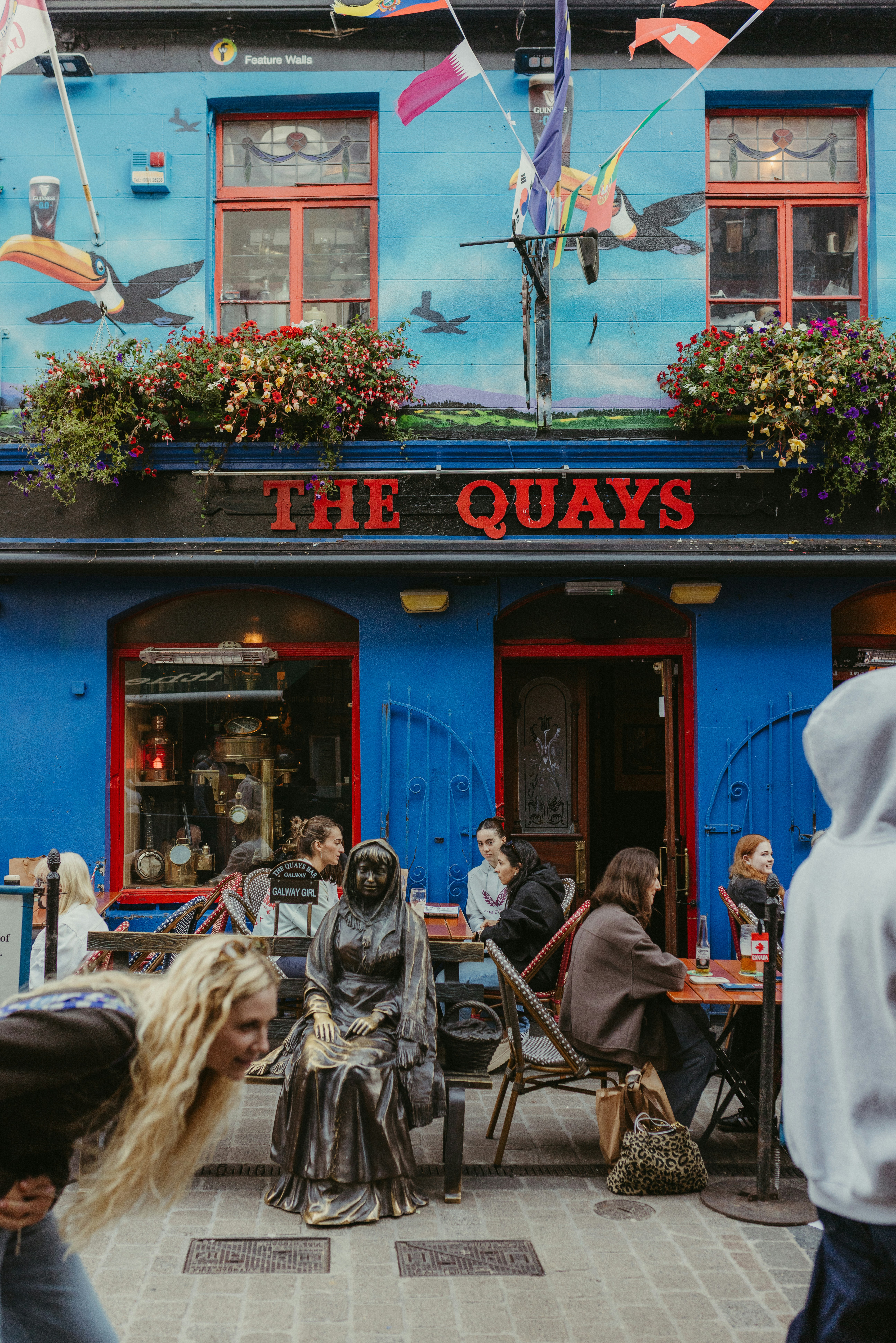 Hooded Statue Amid Café Life at The Quays
