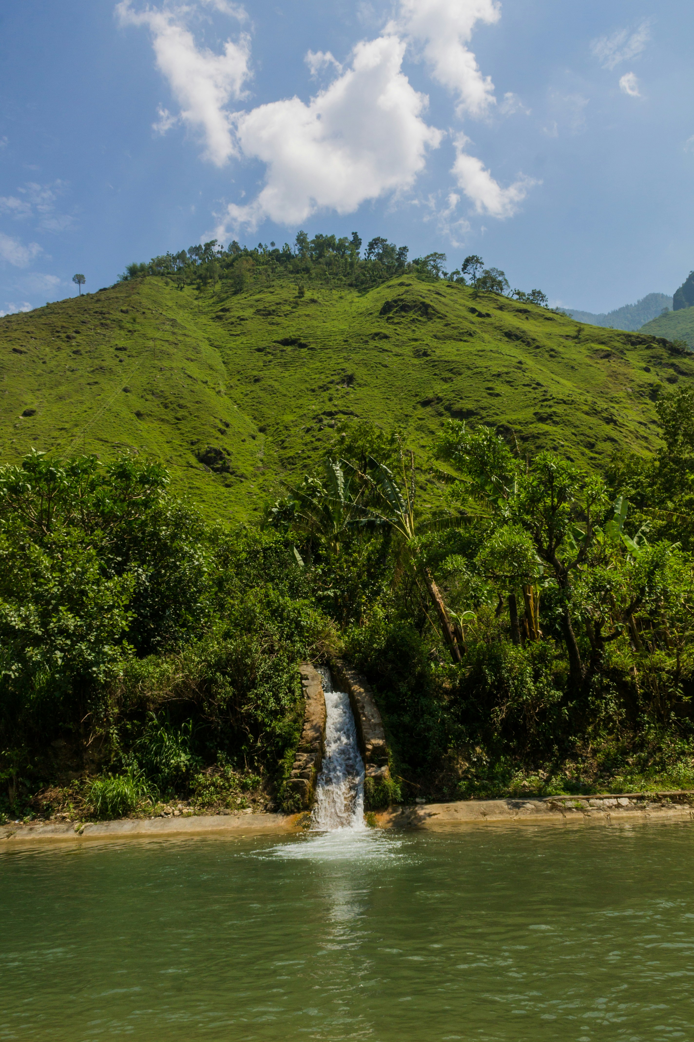 Emerald Cascade at the Lakeside Foot of a Green Hill