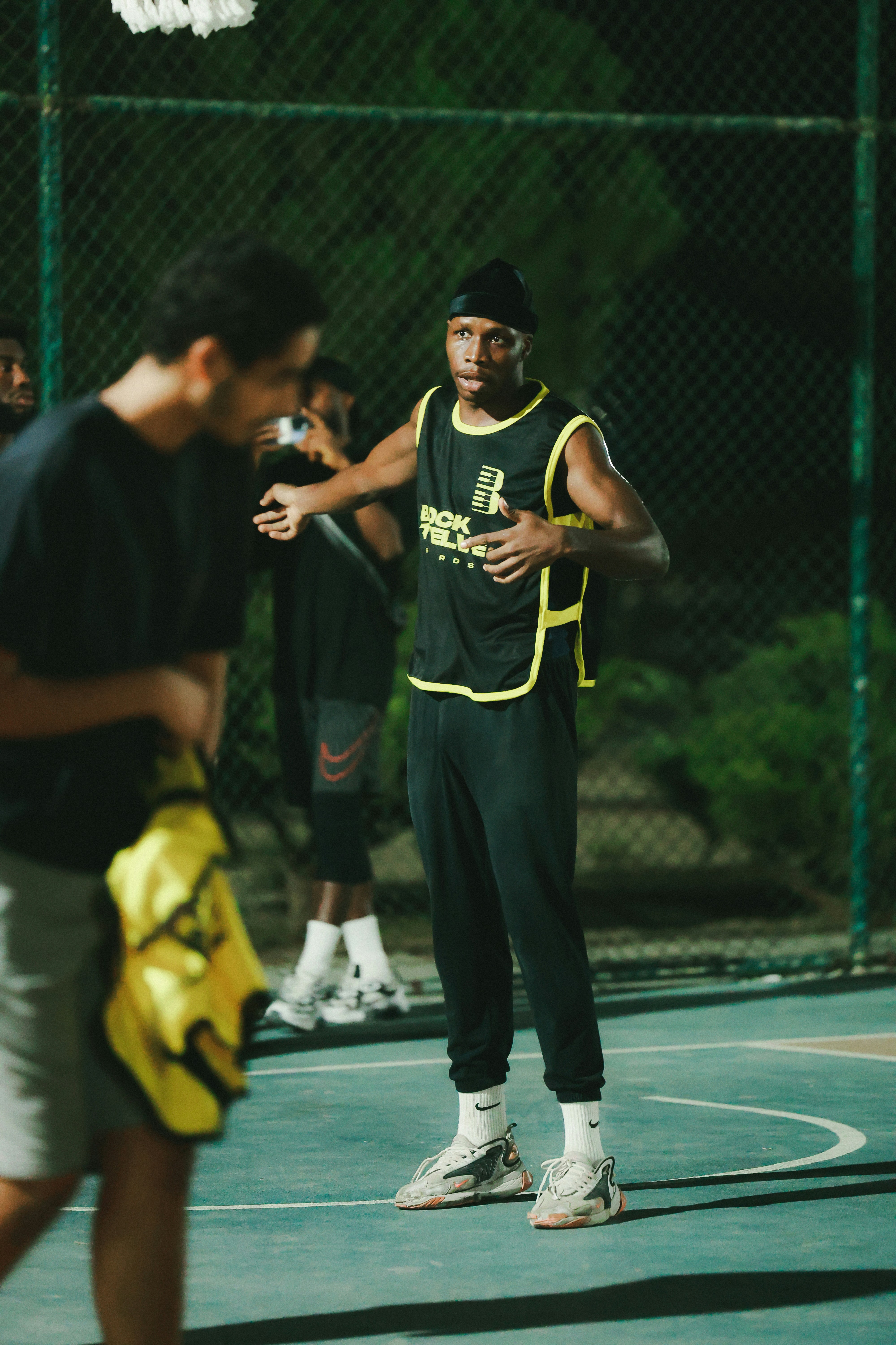 Midnight Courtkeeper: A lone defender anchors a night drill behind a chain-link glow