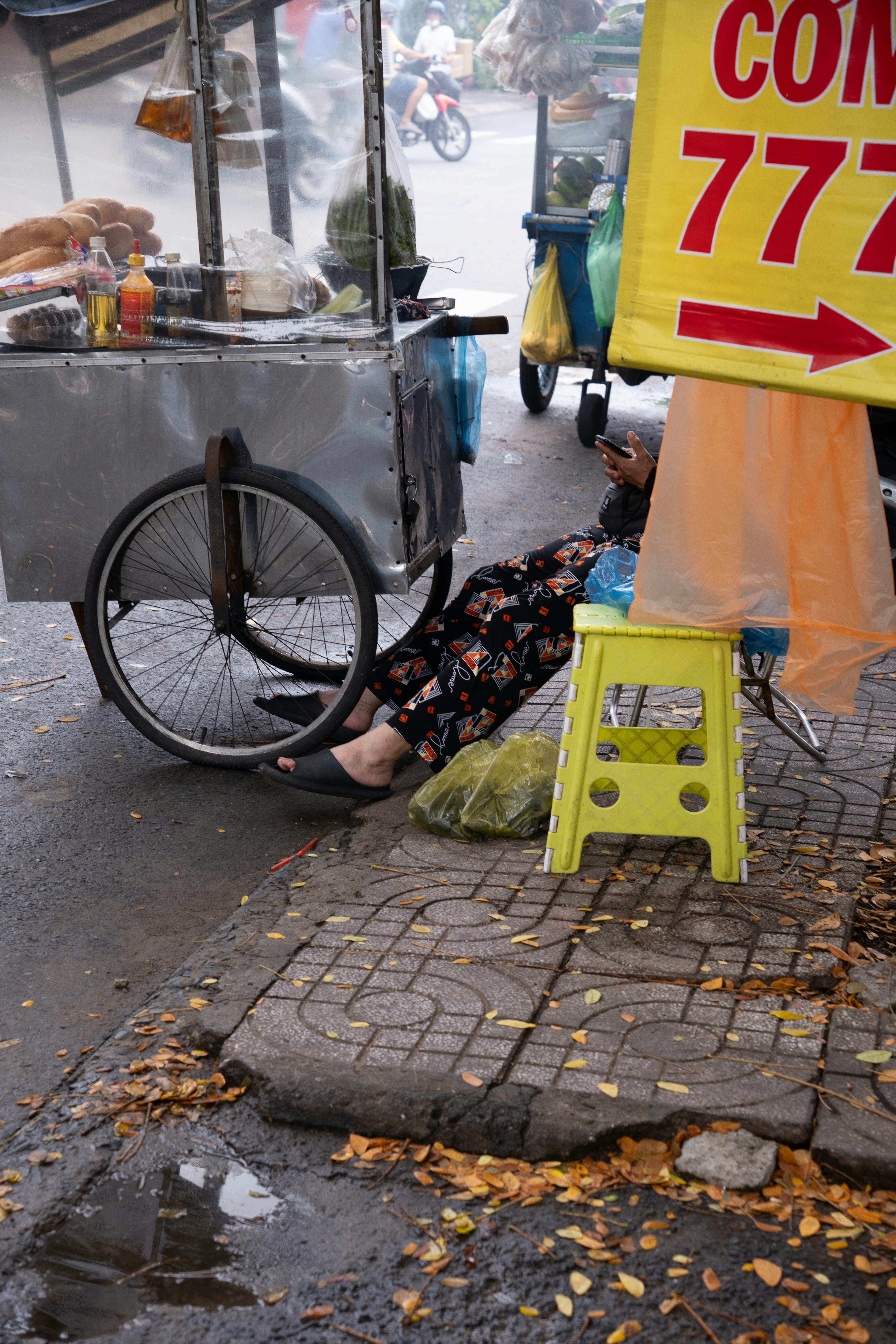 Rain-Washed Street Cart: Quiet Pause Under a Bright Yellow Banner