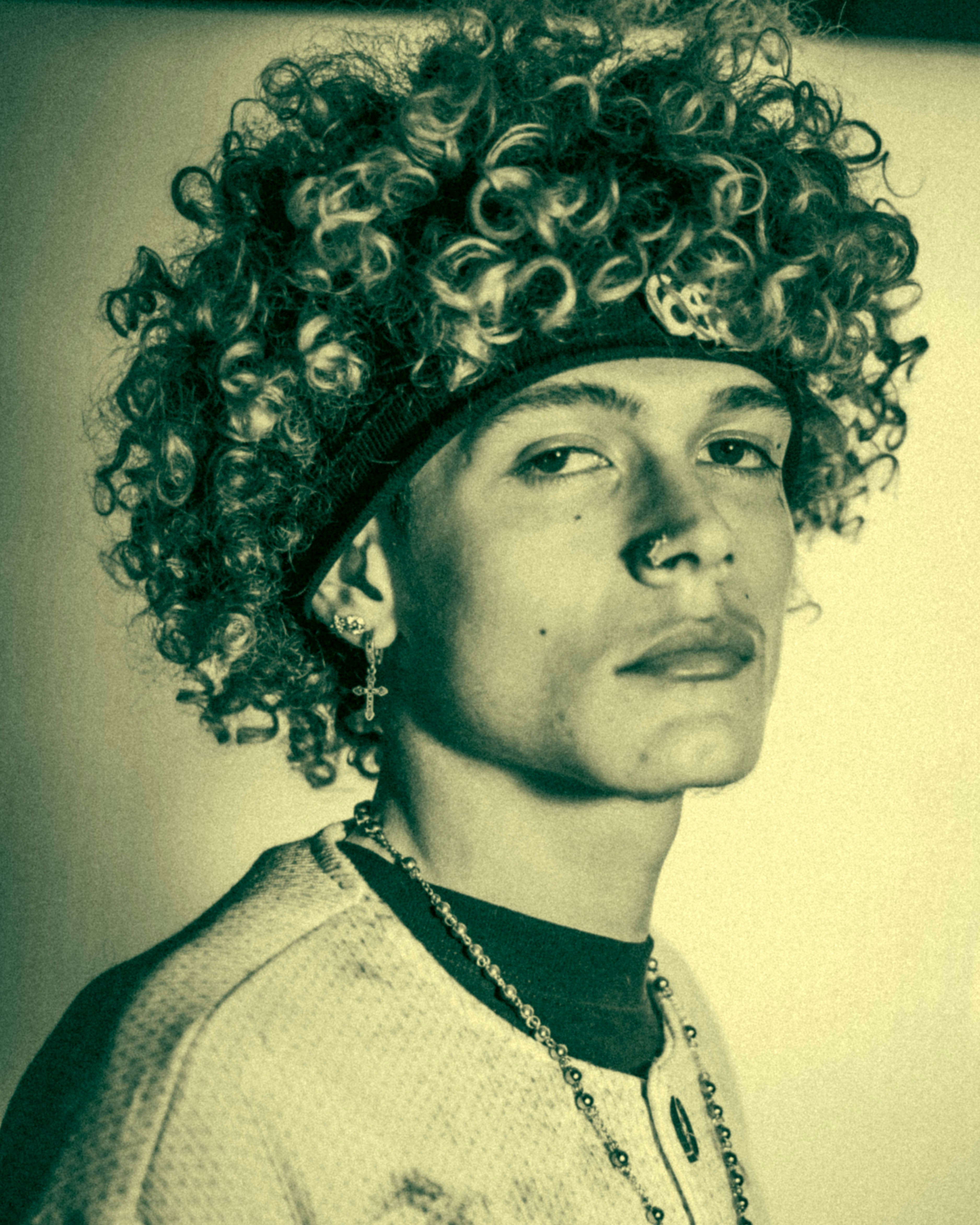 Muted Green Portrait: Curly Hair, Headband, and Cross Necklace