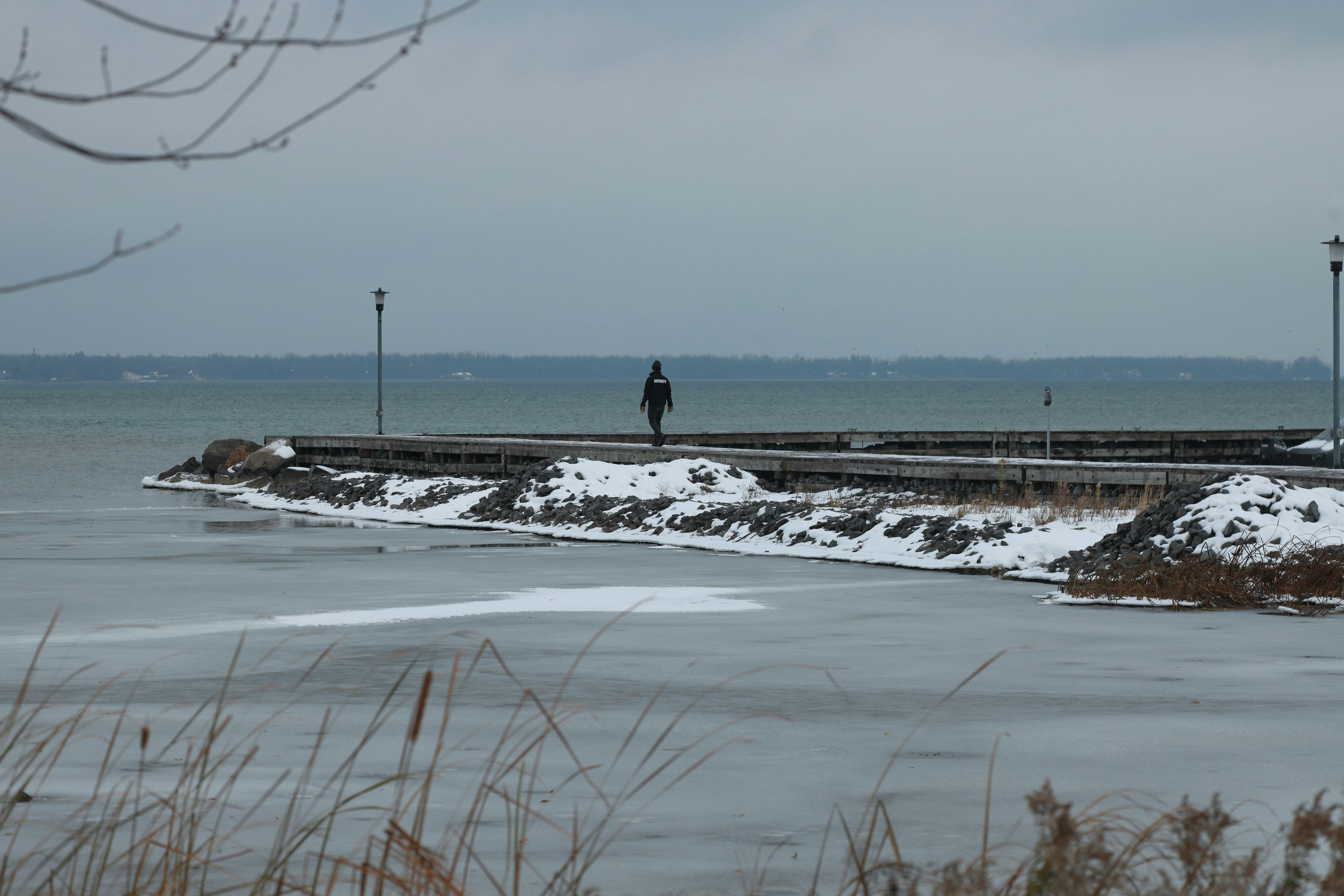 Person walking on a pier by a frozen lake