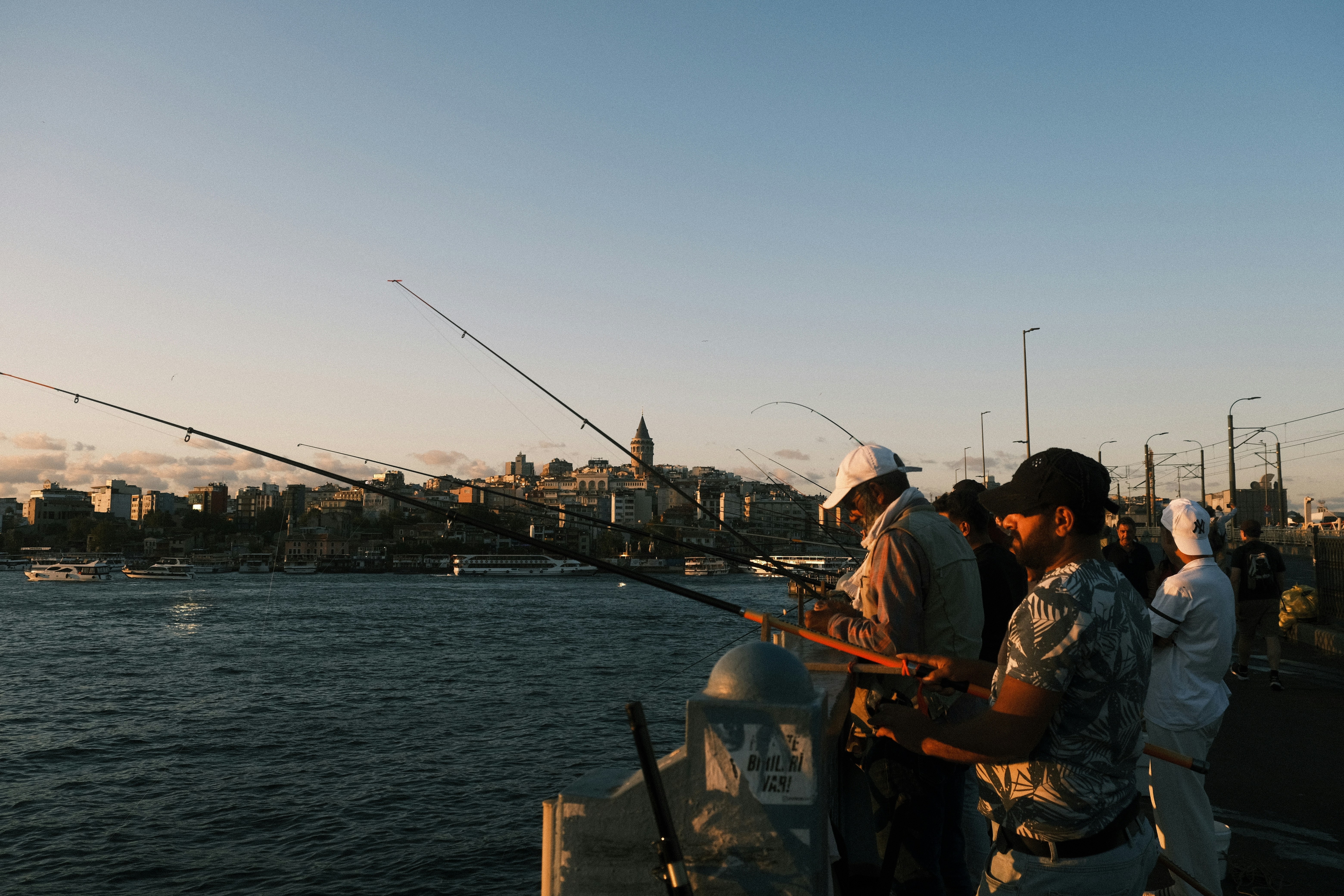 Dusk on the Pier: A Fisherman's Focus Beneath the Cityscape